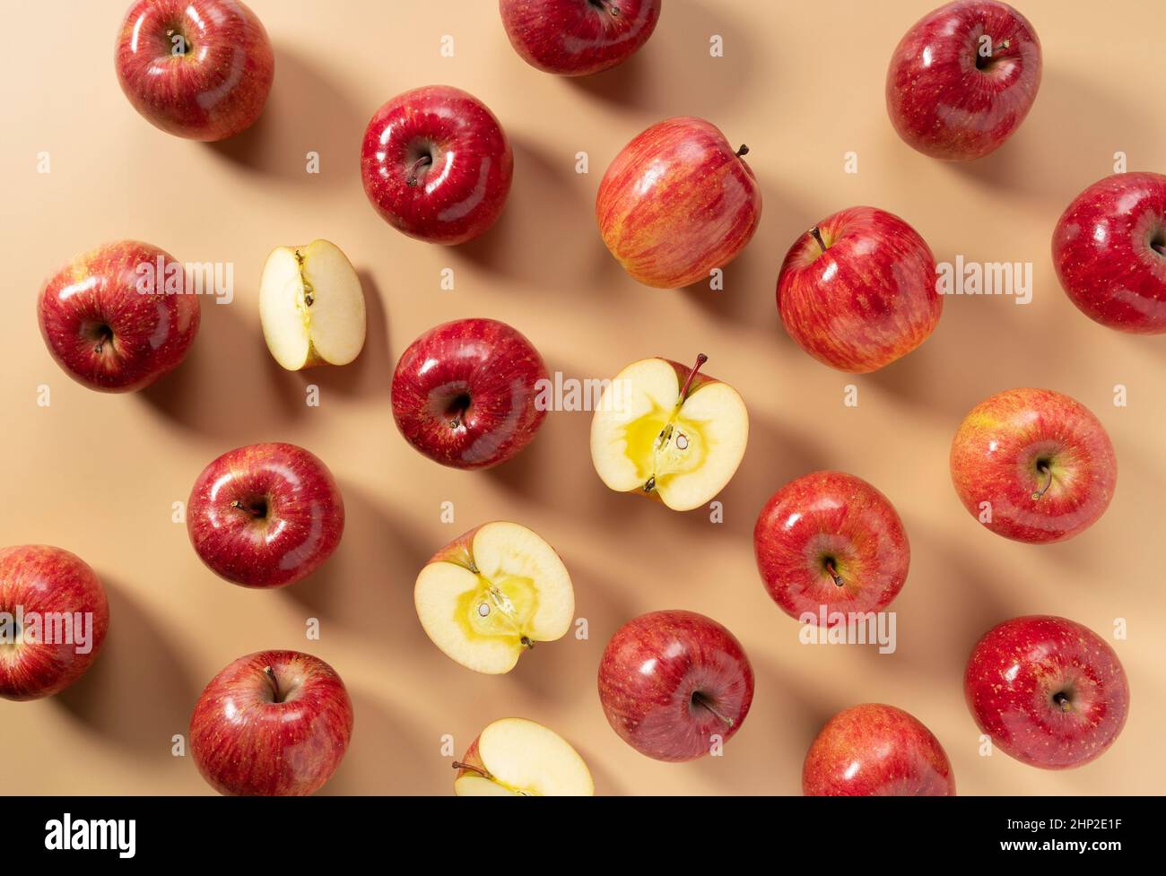 A lot of apples placed on a beige background, cut in half or quarter ...