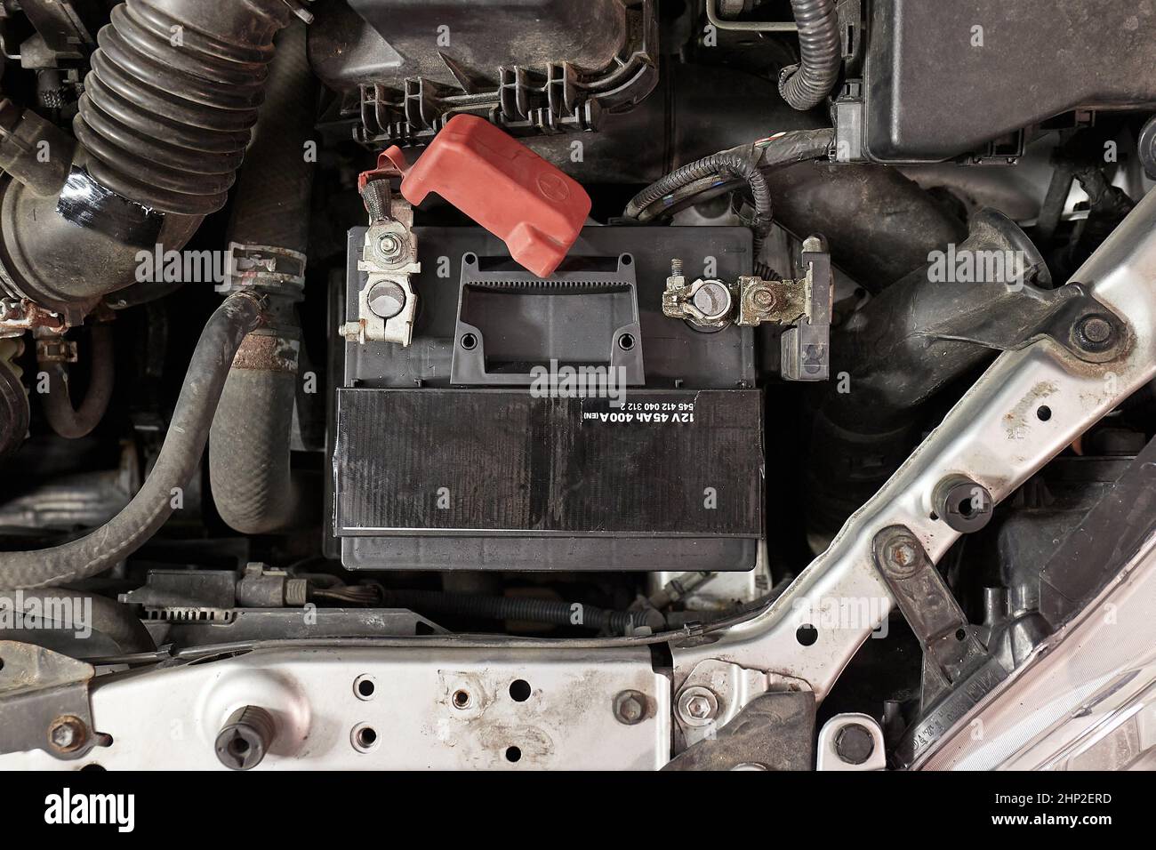 Old car starter battery inside the engine bay viewed from above top ...