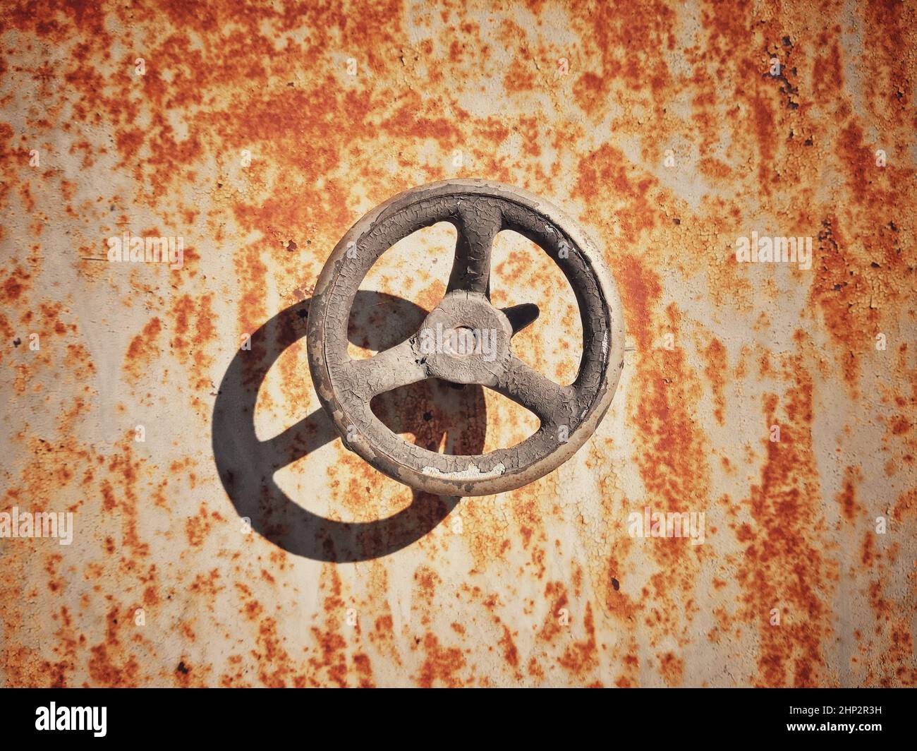 Old damaged and rusty iron oil pipe valve wheel on a metal wall Stock ...