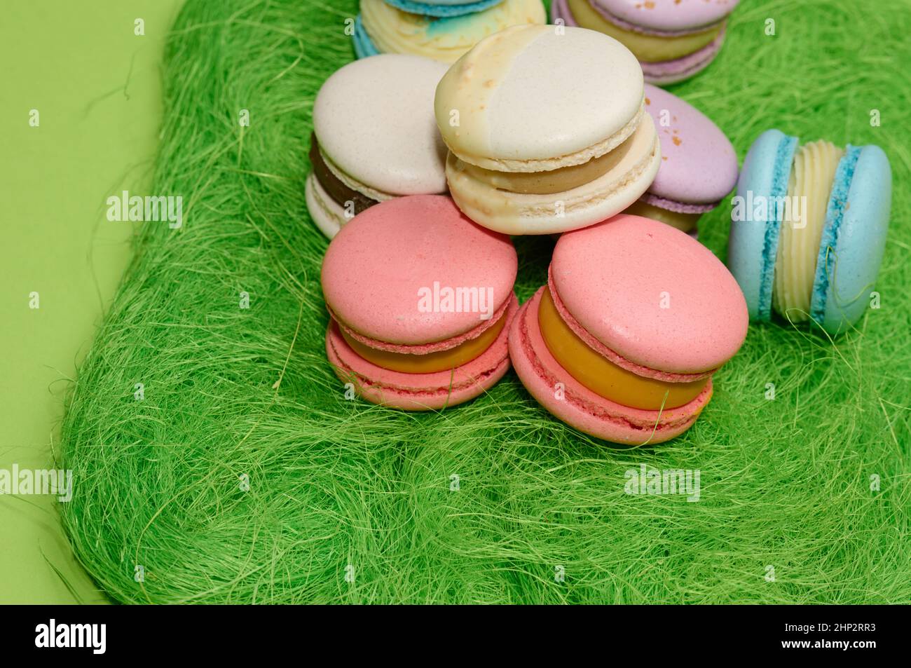 baked macarons with different flavors on a green background, top view ...