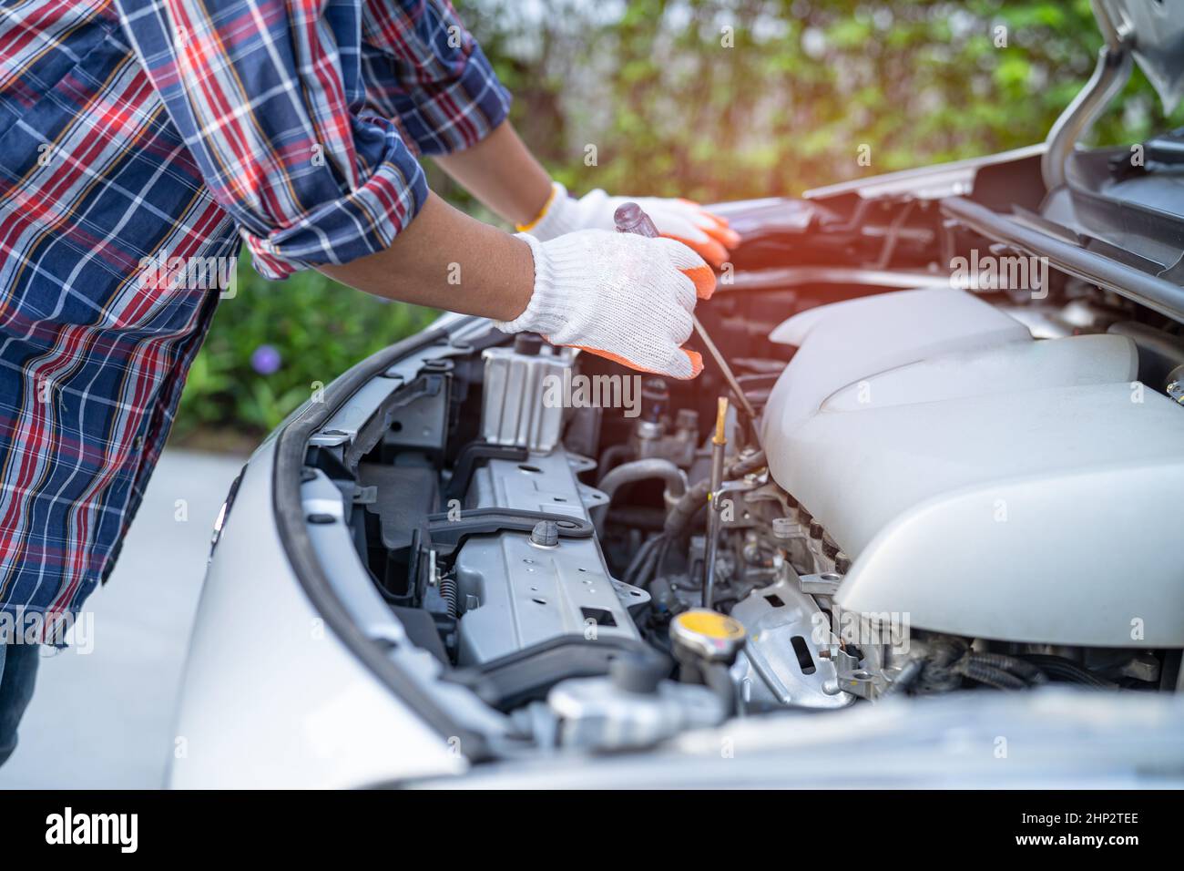 Asian auto mechanic check for repair under the hood of broken down car ...