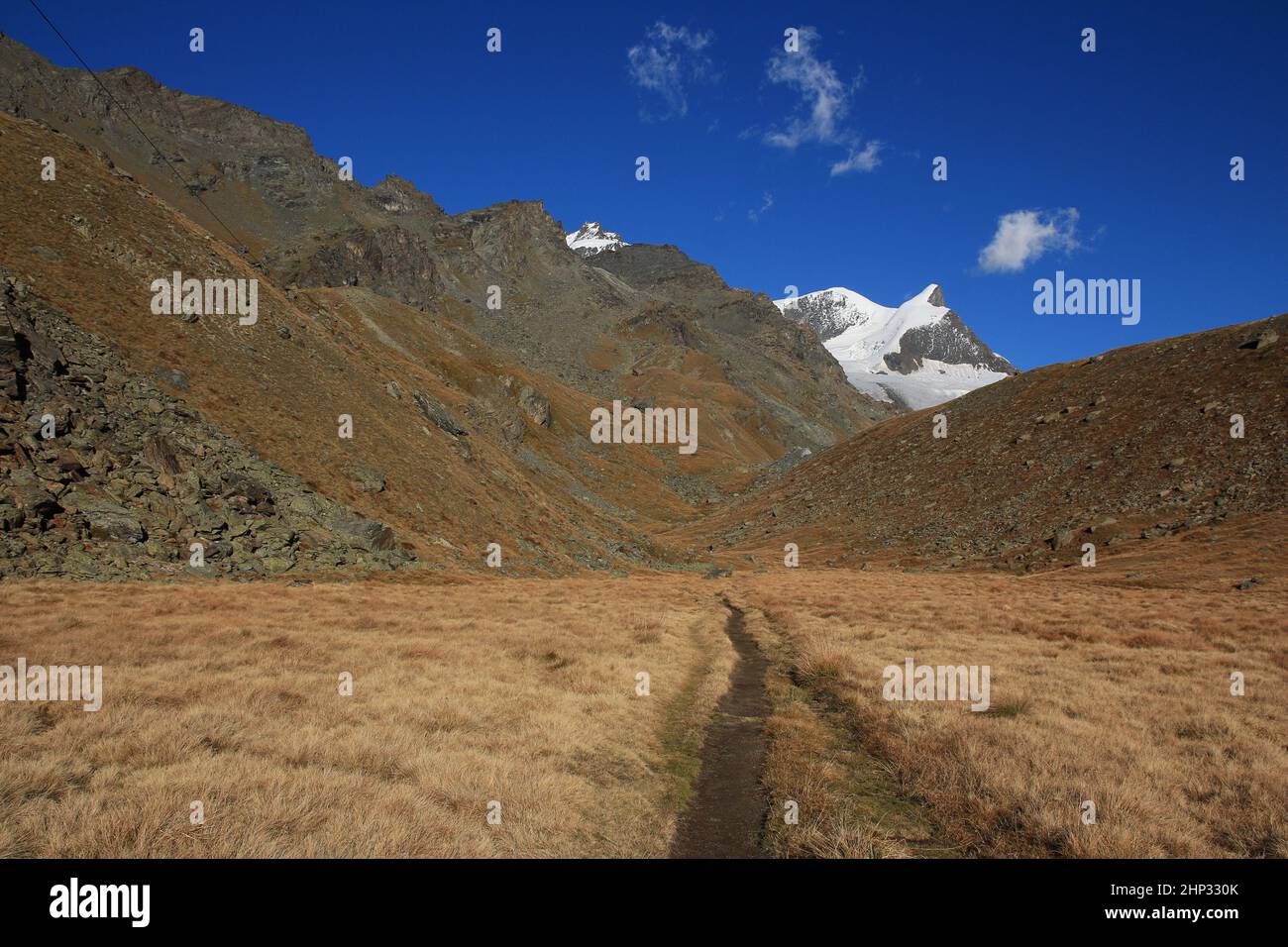 Foot path and distant view of a snow capped mountain Stock Photo - Alamy