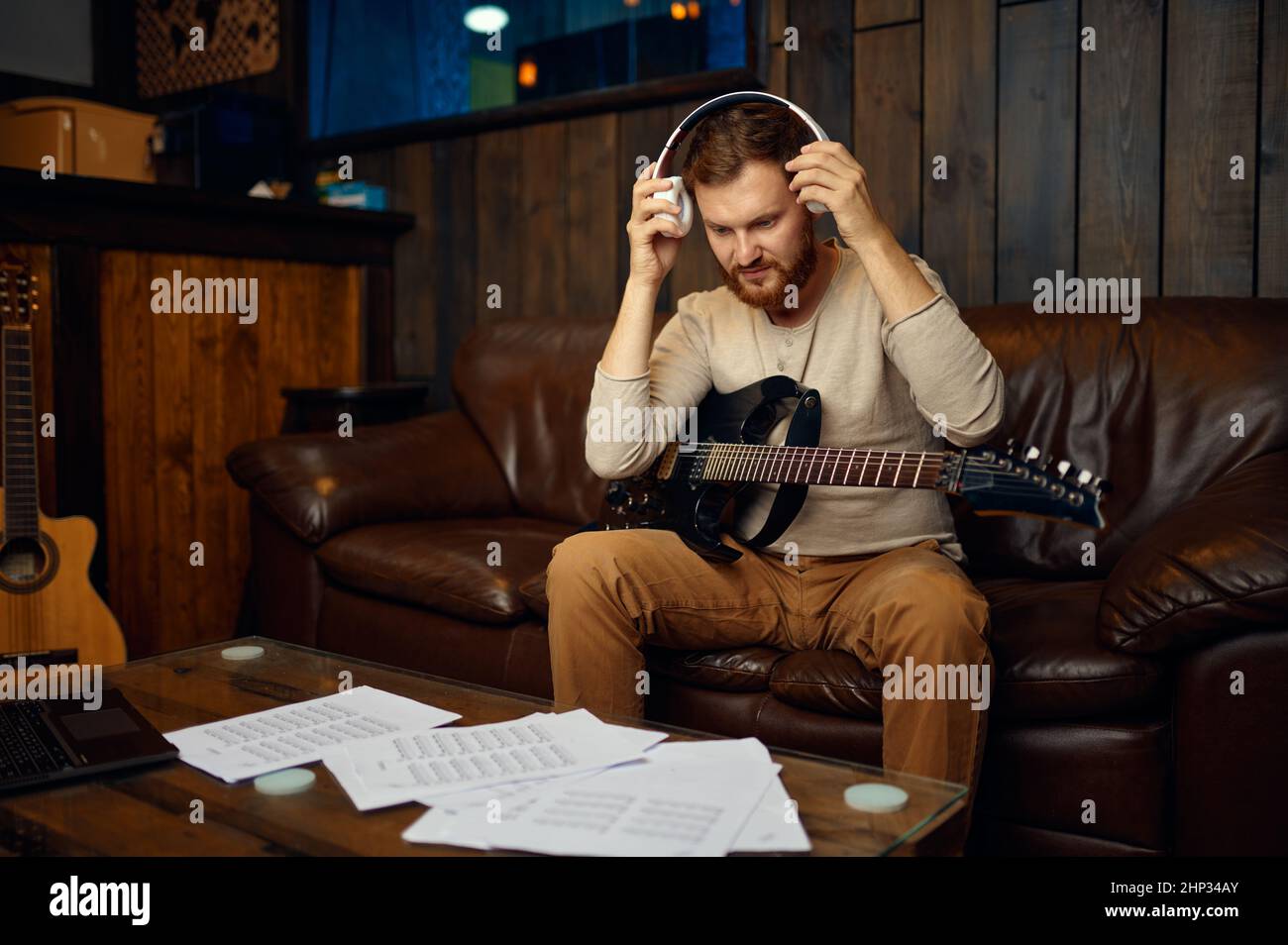 Man taking off headphones finish music lesson. Guy sitting with guitar ...