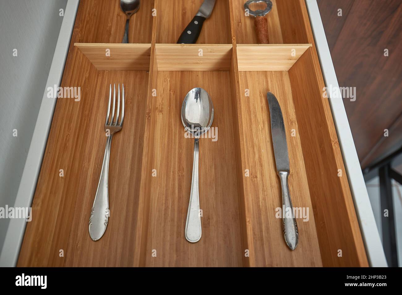 Puting one piece of types of cutlery in the drawer of the kitchen ...
