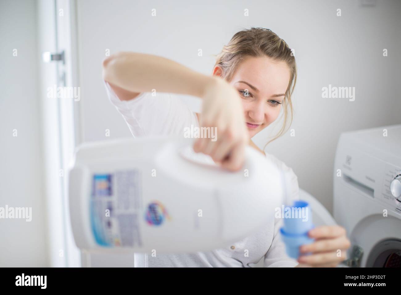 Housework: young woman doing laundry - putting colorful garments into ...
