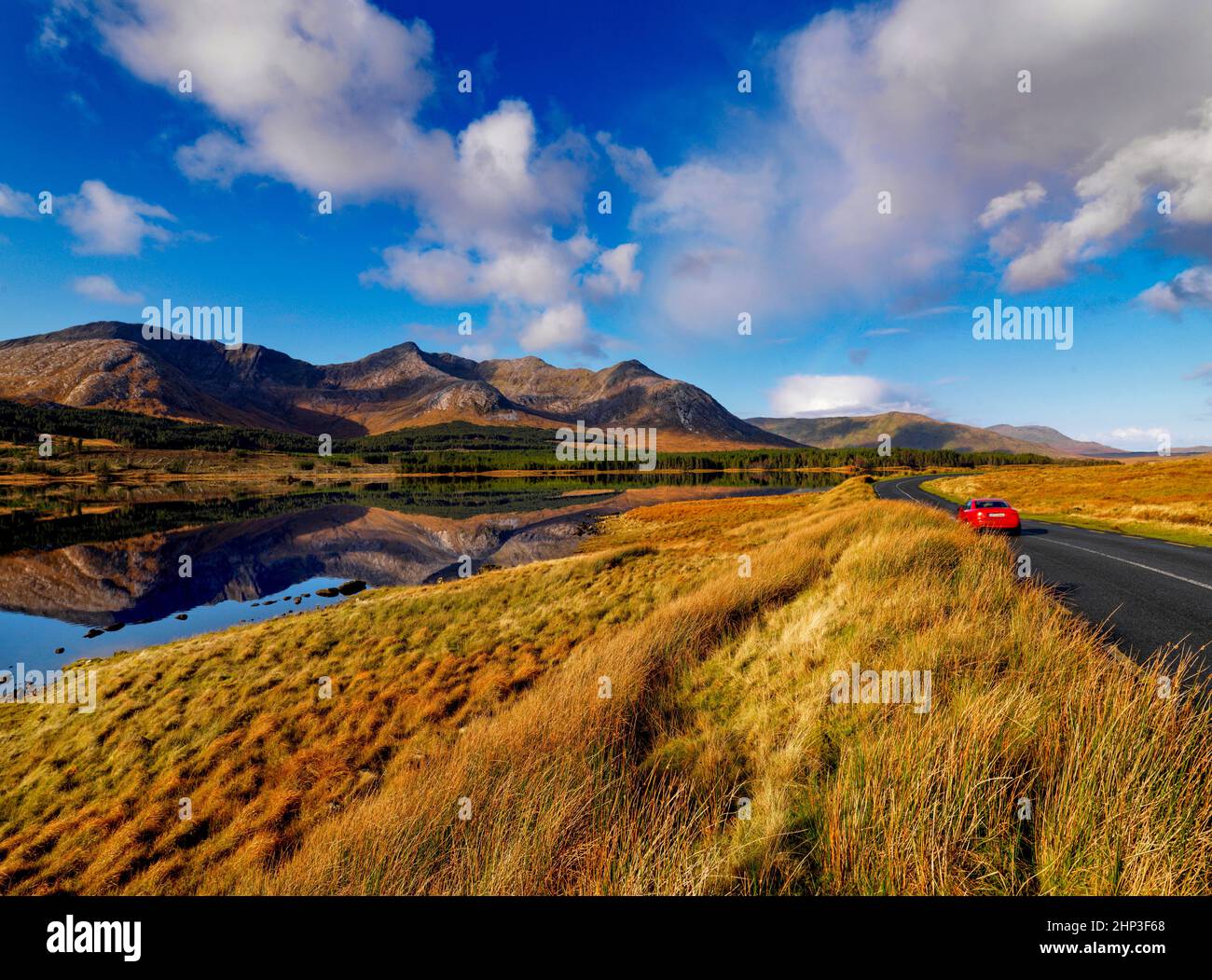 A car driving on a road trip past Lough Inagh, Connemara, Co. Galway ...