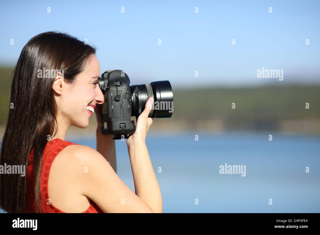 Side view portrait of a happy photographer taking photos in a lake ...