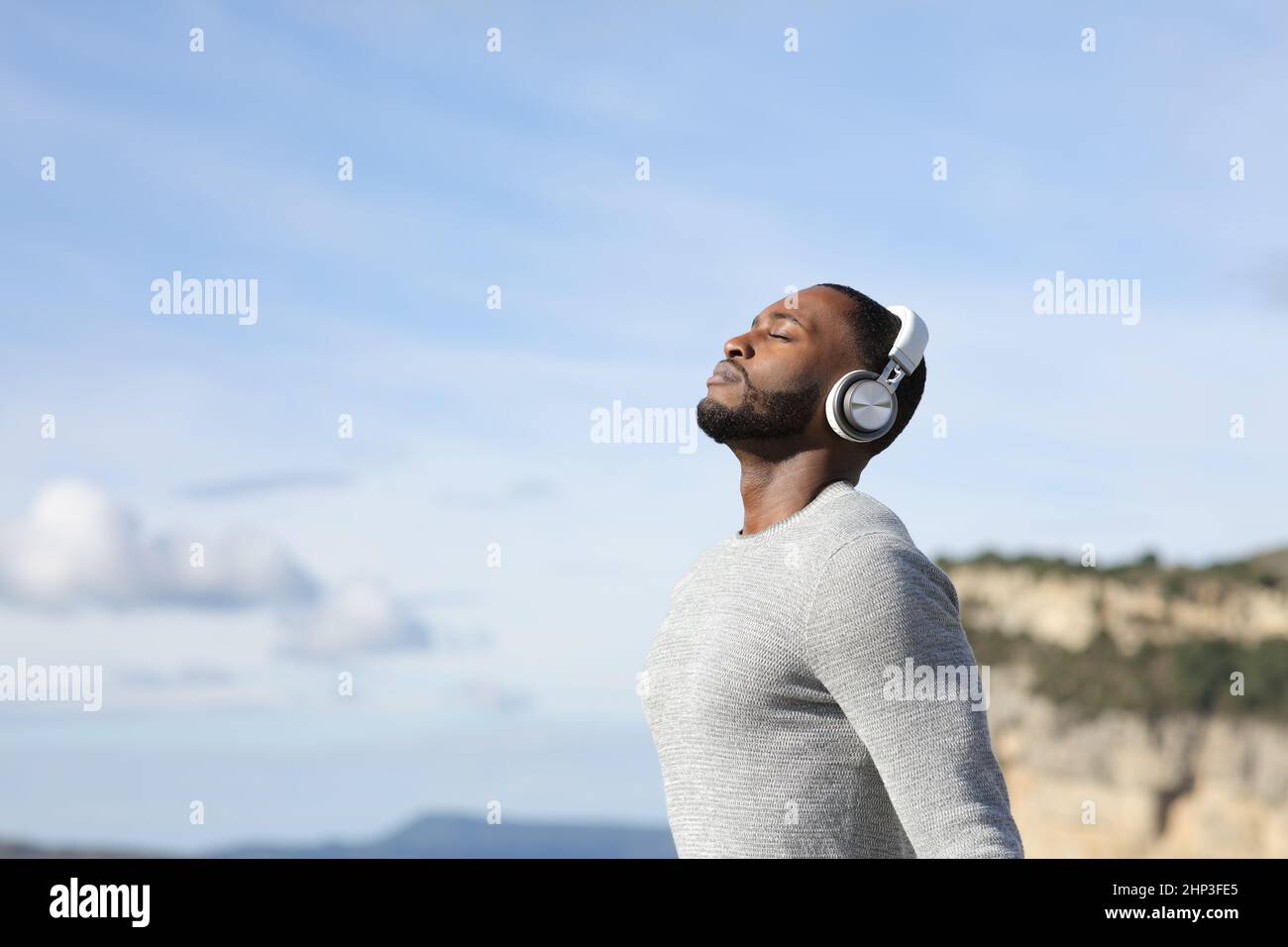 Relaxed man with black skin wearing wireless headphones meditating ...