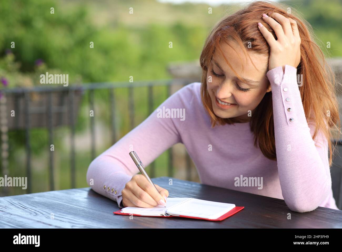 Happy woman writing in paper agenda in a balcony smiling Stock Photo ...