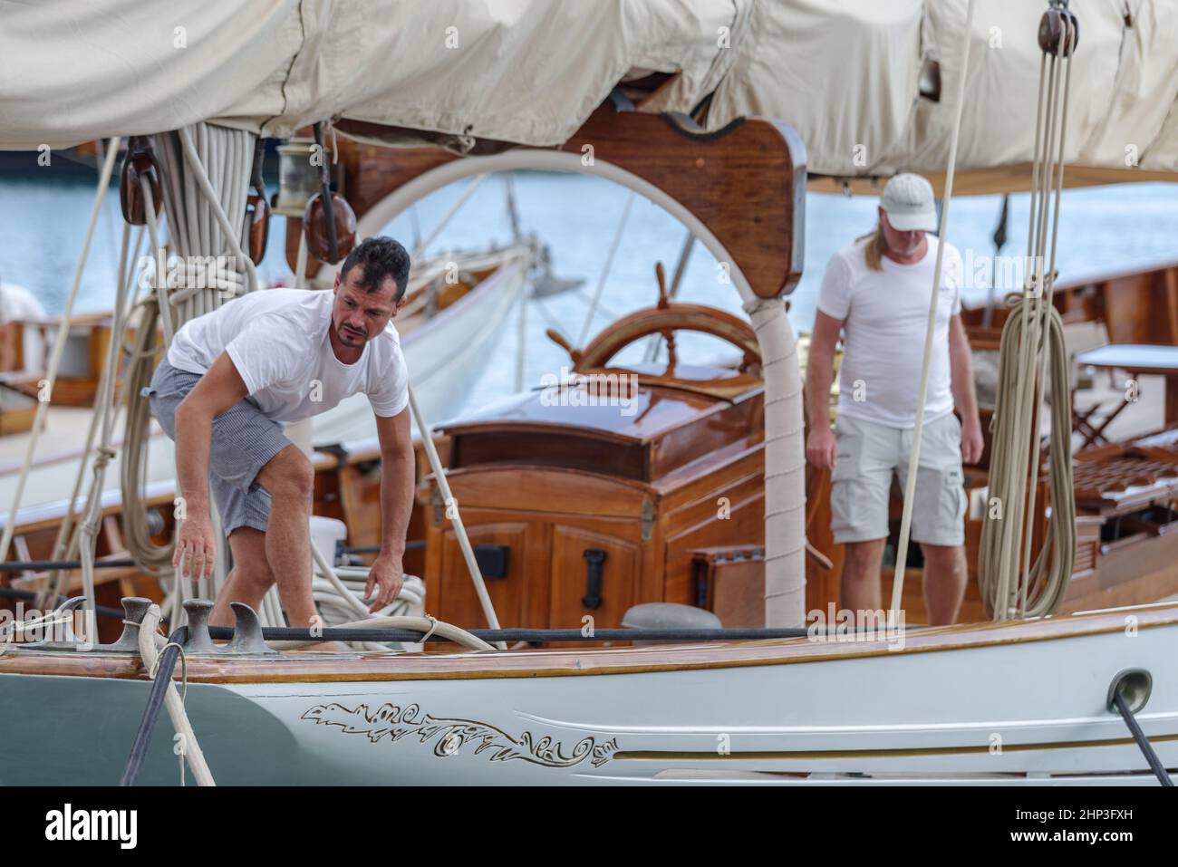 Crew members in action on sailboat moored in the harbour of Imperia ...
