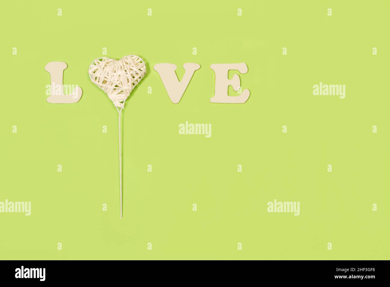 Love word in wooden letters and a paper heart on a green background ...