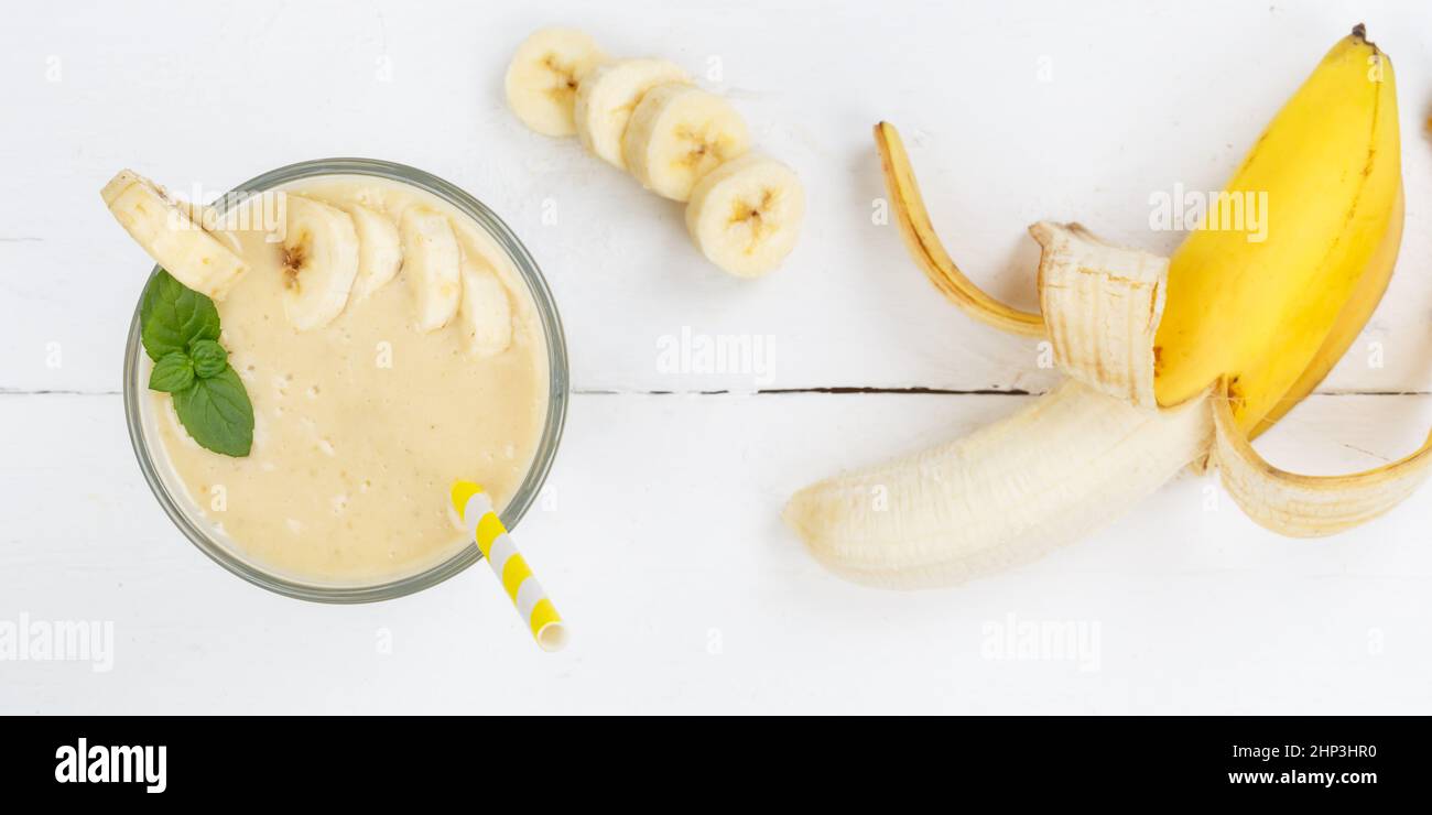 Banana fruit juice smoothie fresh drink in a glass from above panorama ...