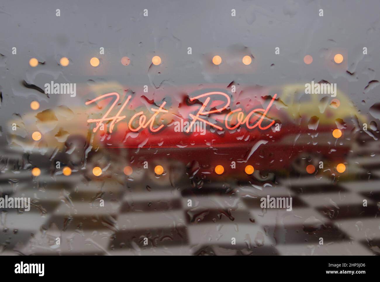 Neon Hot Rod Sign in wet window with vintage hot rod car in background ...