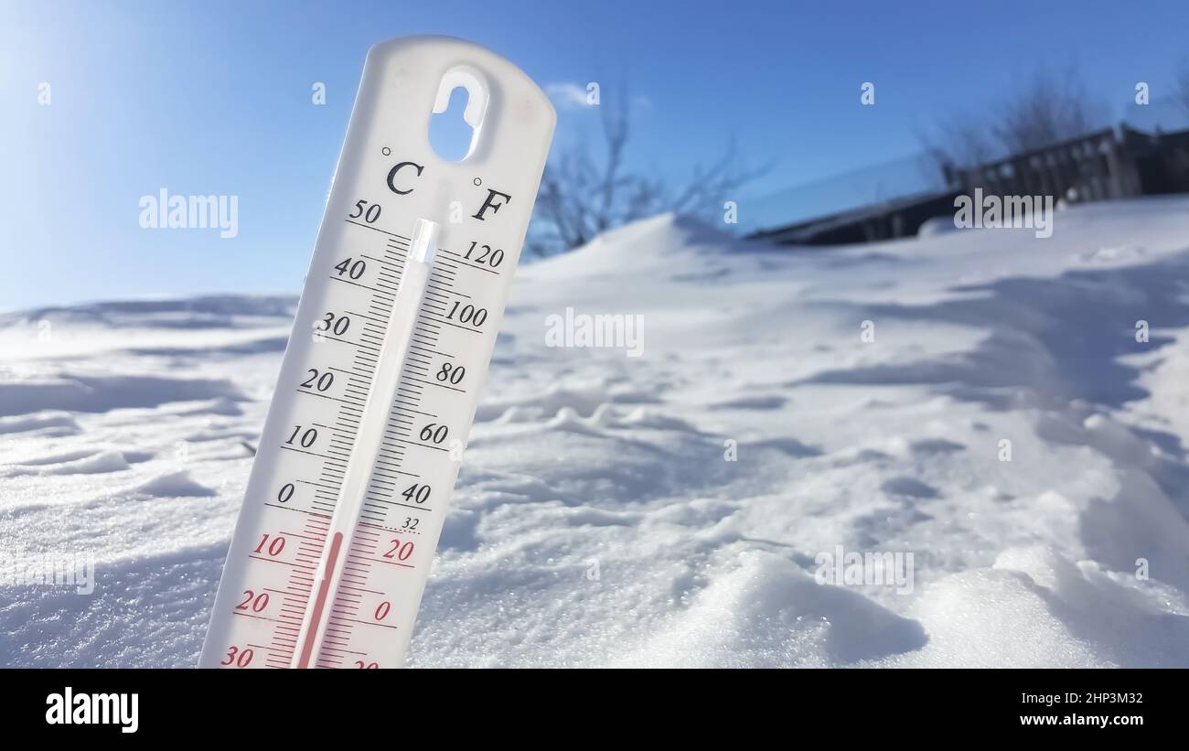 The thermometer in winter lies on the snow and shows low negative air ...