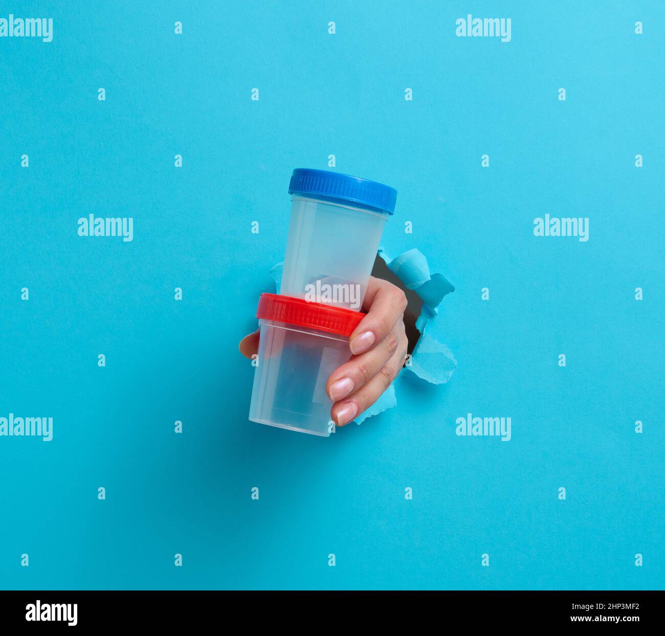 female hand holds an empty plastic jar for urine tests, the hand is ...