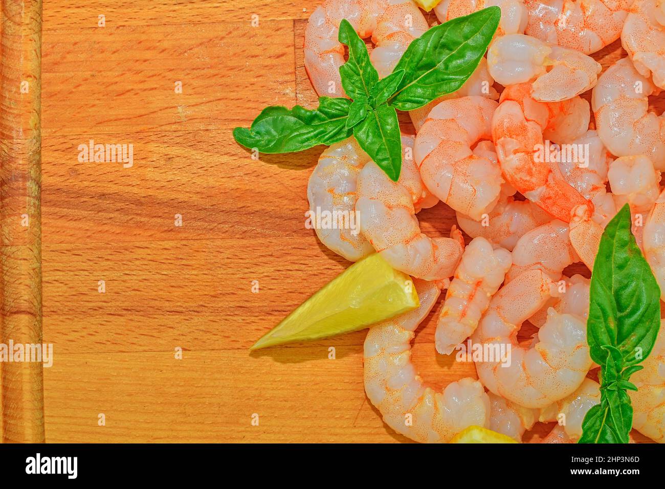Cooked and peeled prawns with slices of lemon and leaves of basil on ...