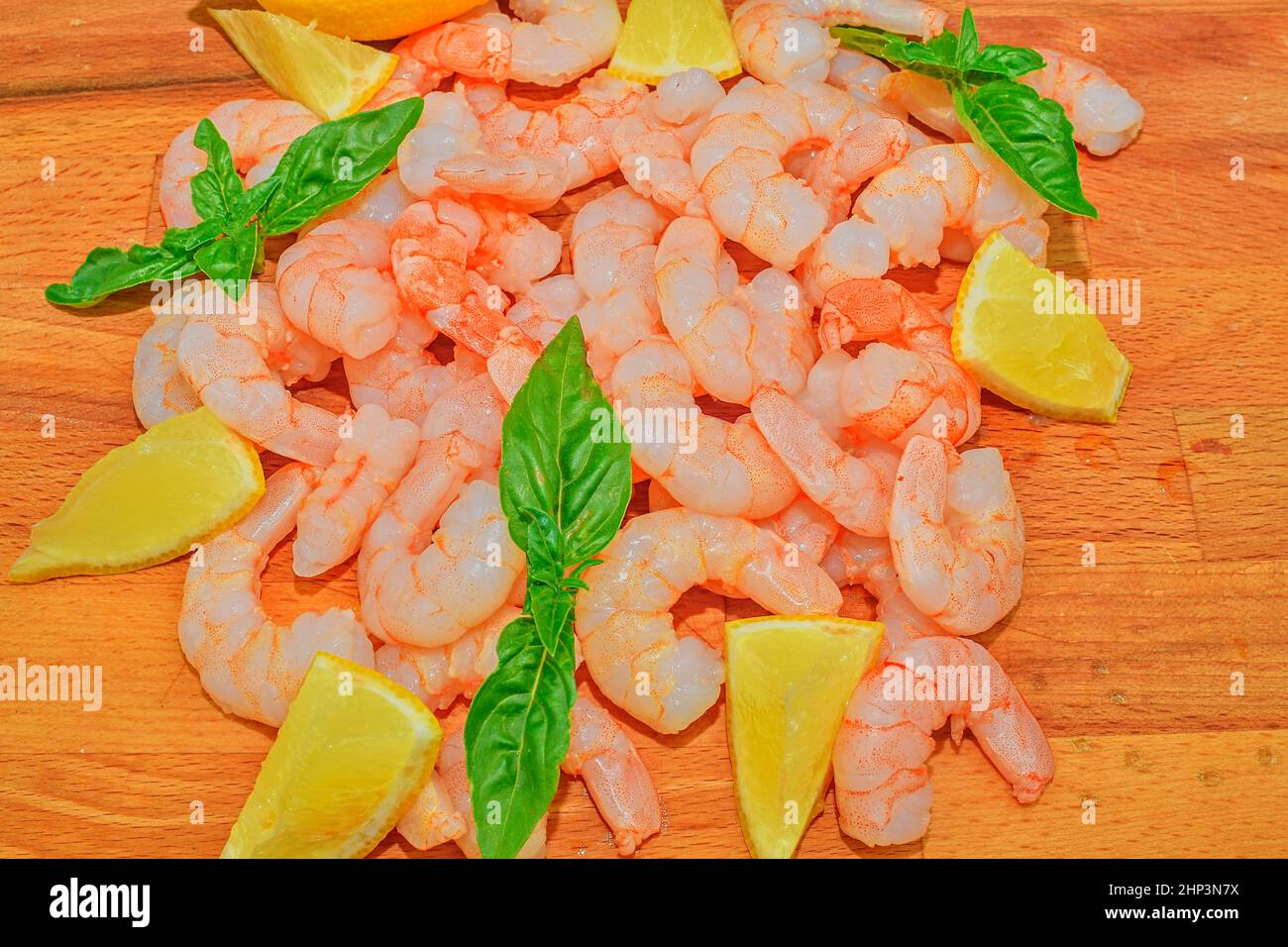 Cooked and peeled prawns with slices of lemon and leaves of basil on ...