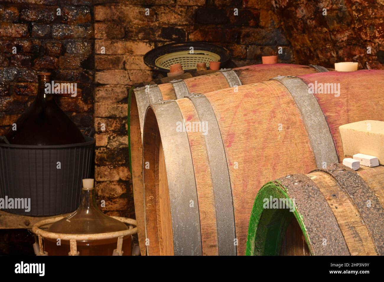 Old wine cellar with demijohns and wooden barrels. Making wine ...