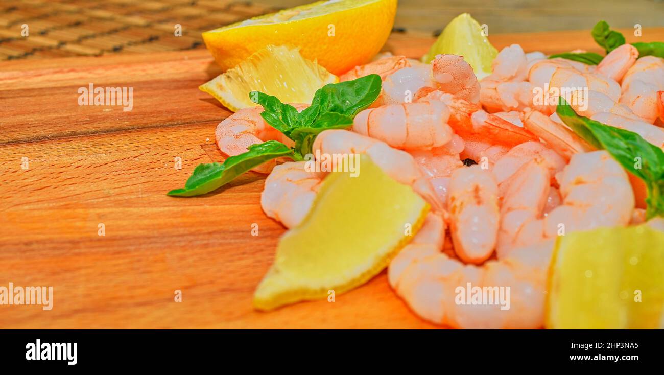 Cooked and peeled prawns with slices of lemon and leaves of basil on ...