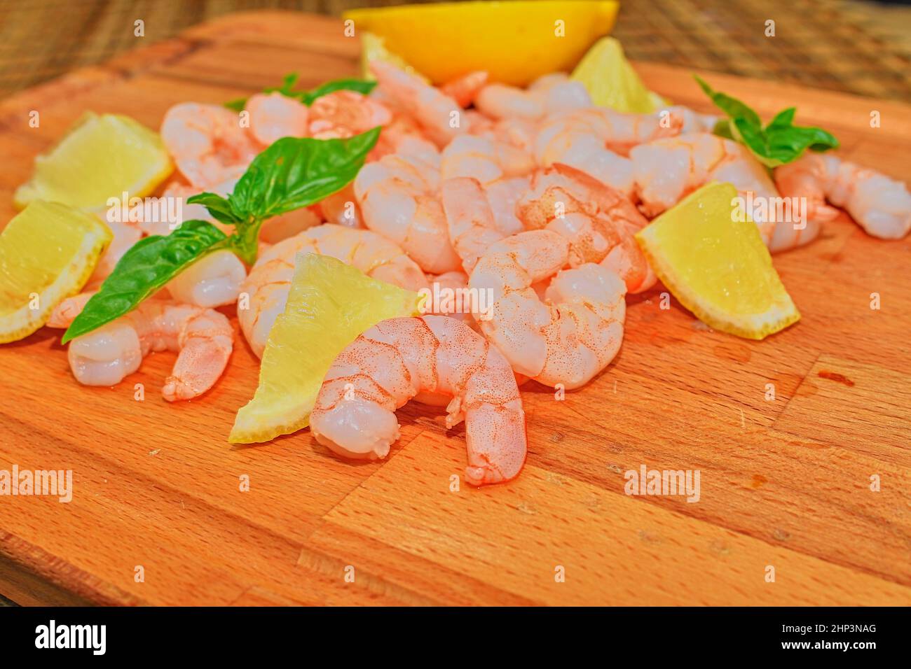 Cooked and peeled prawns with slices of lemon and leaves of basil on ...