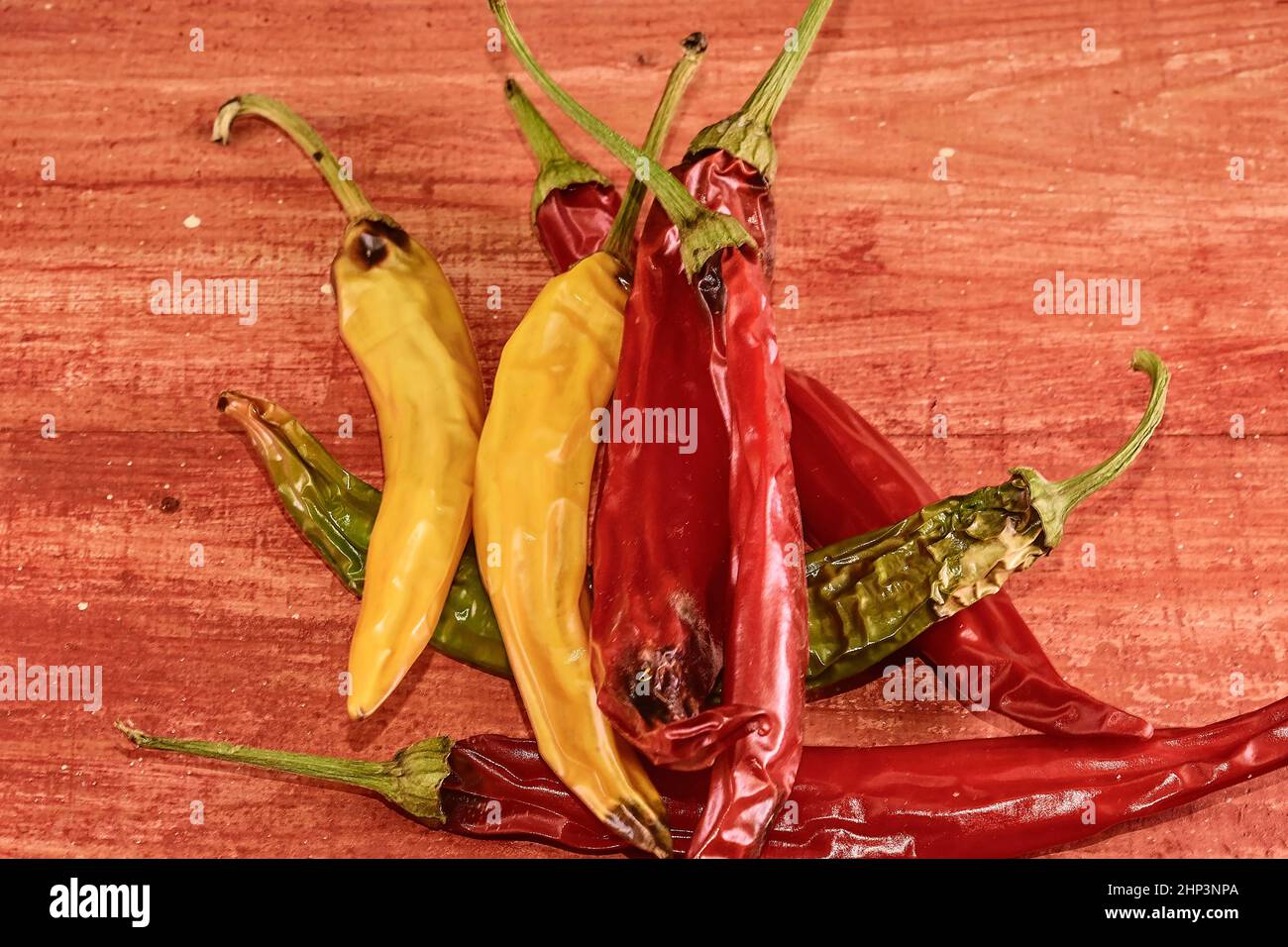 Shrinking and mould chili peppers on red wooden background. Rotten ...