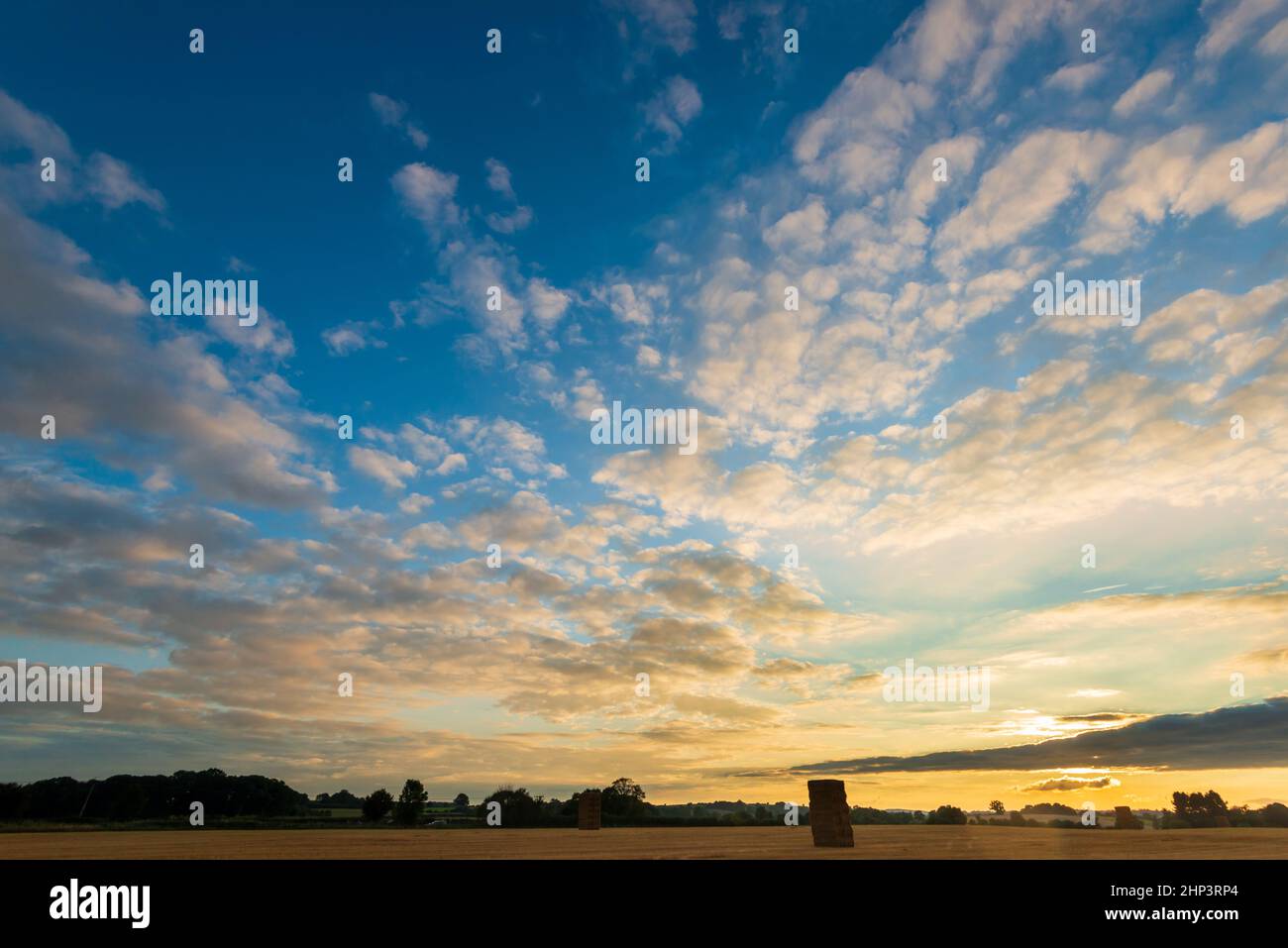 Altocumulus clouds give an attractive sunset over a field of harvested ...