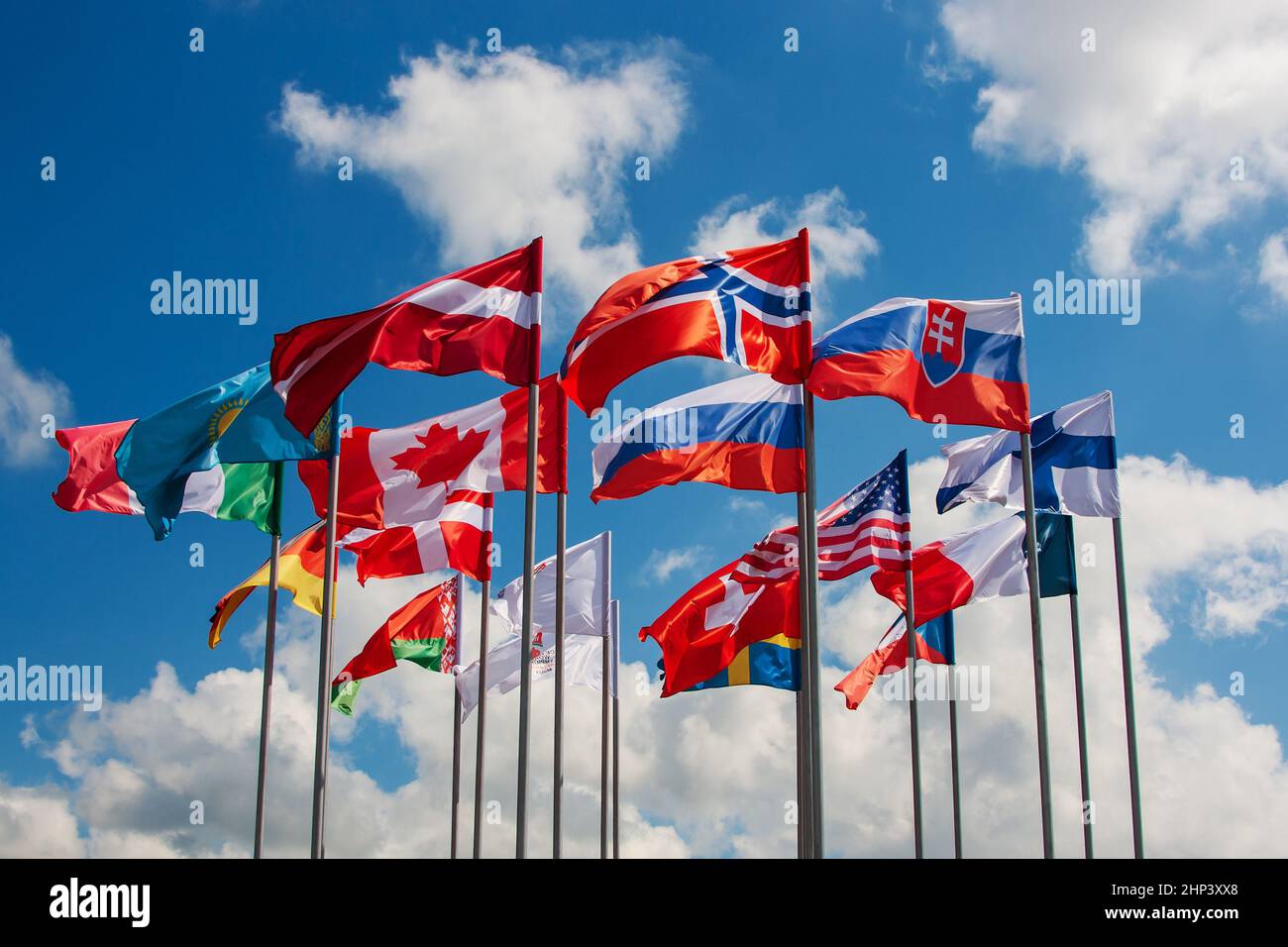 Bright flags of different countries against the blue sky and clouds ...