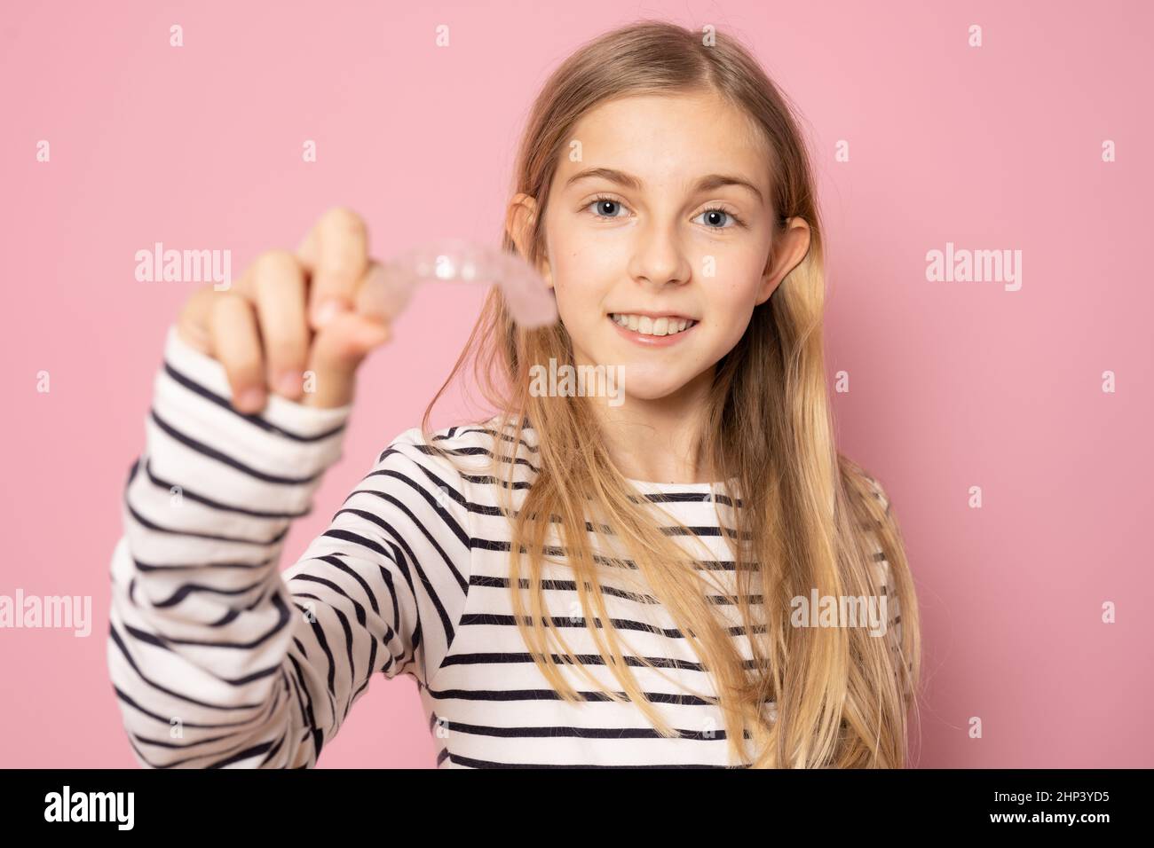 Beautiful young girl showing orthodontic silicone trainer isolated over ...