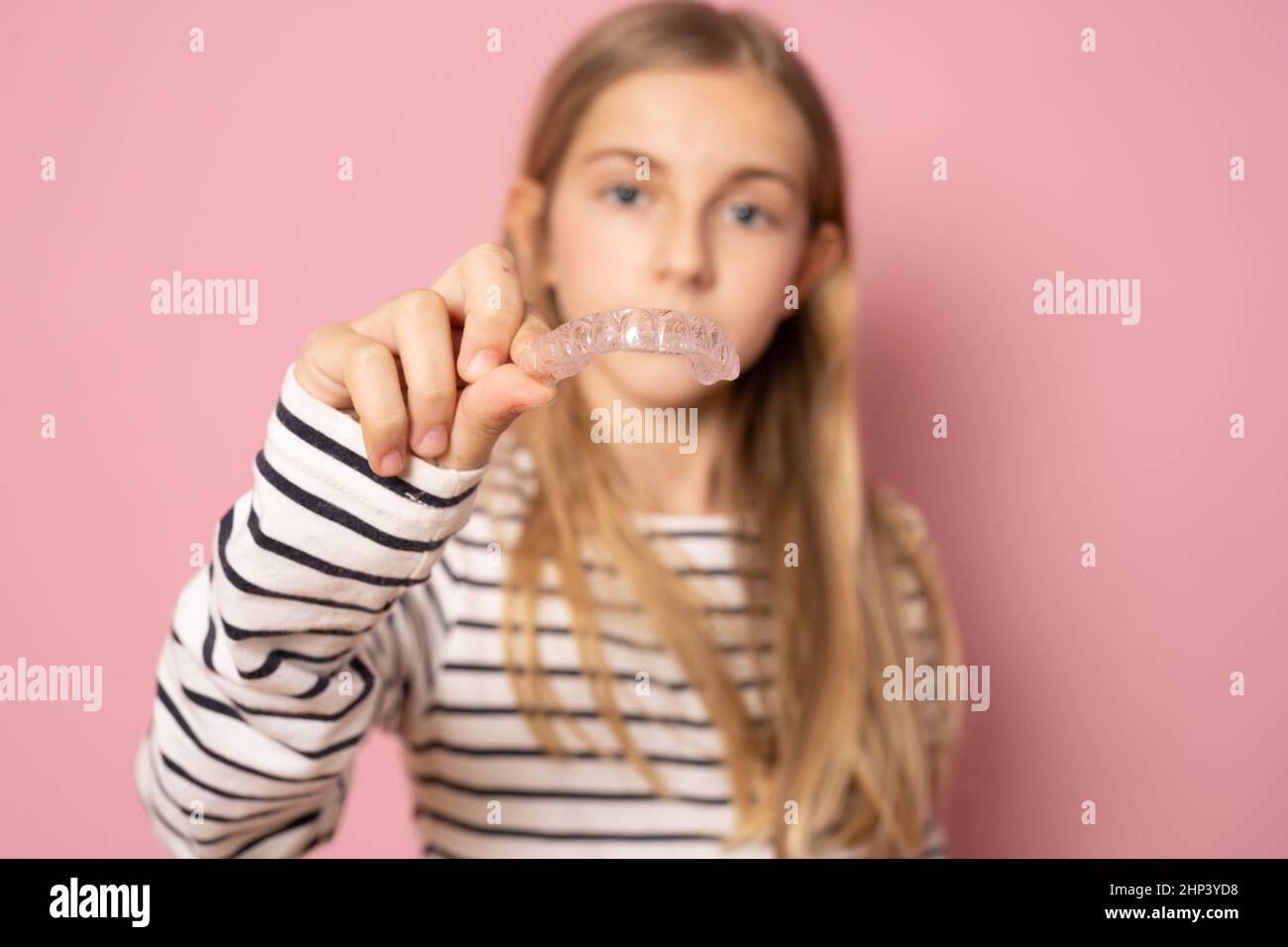 Beautiful young girl showing orthodontic silicone trainer isolated over ...