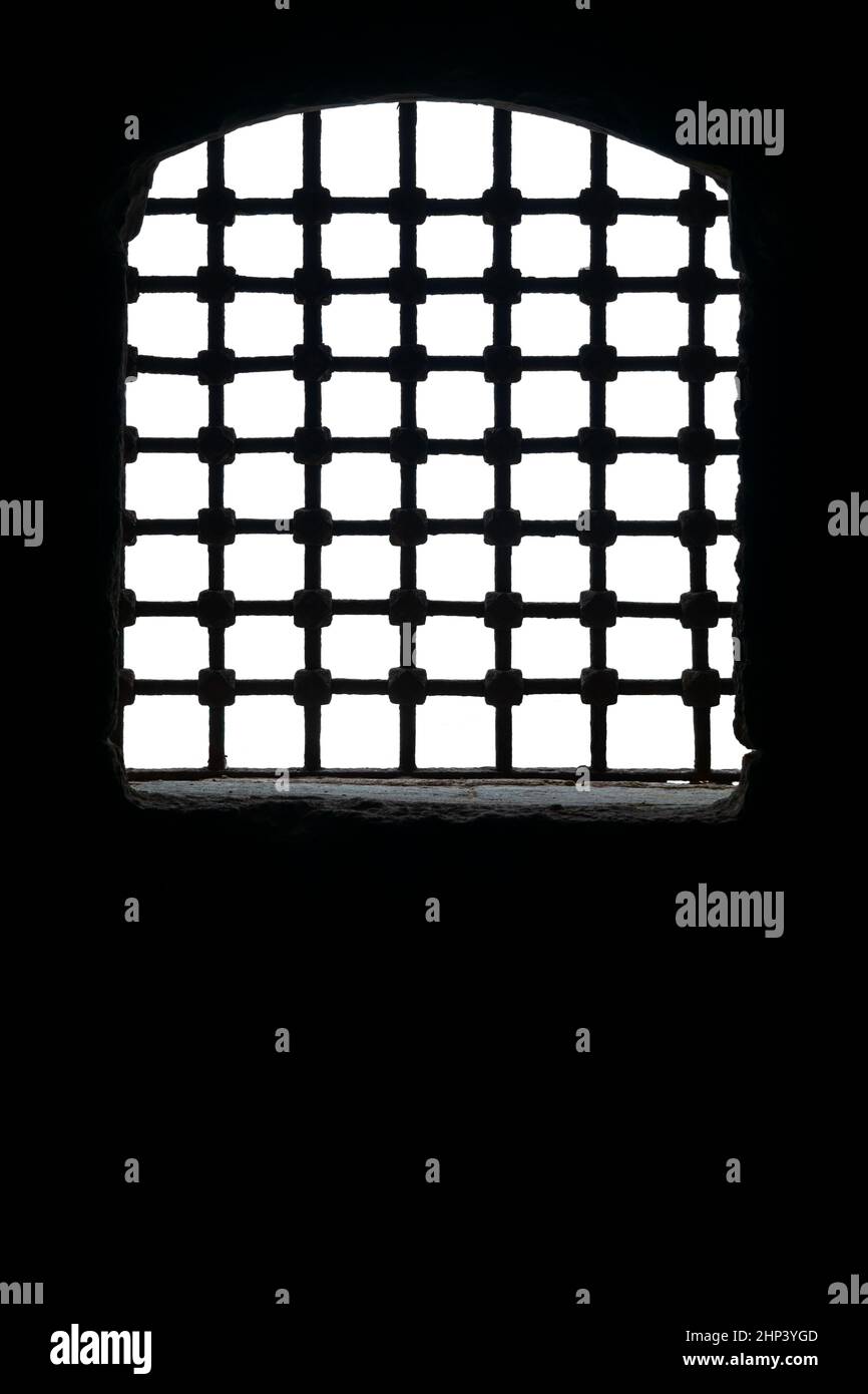 Cut out of arched window with metal grid in dark room of aged building ...