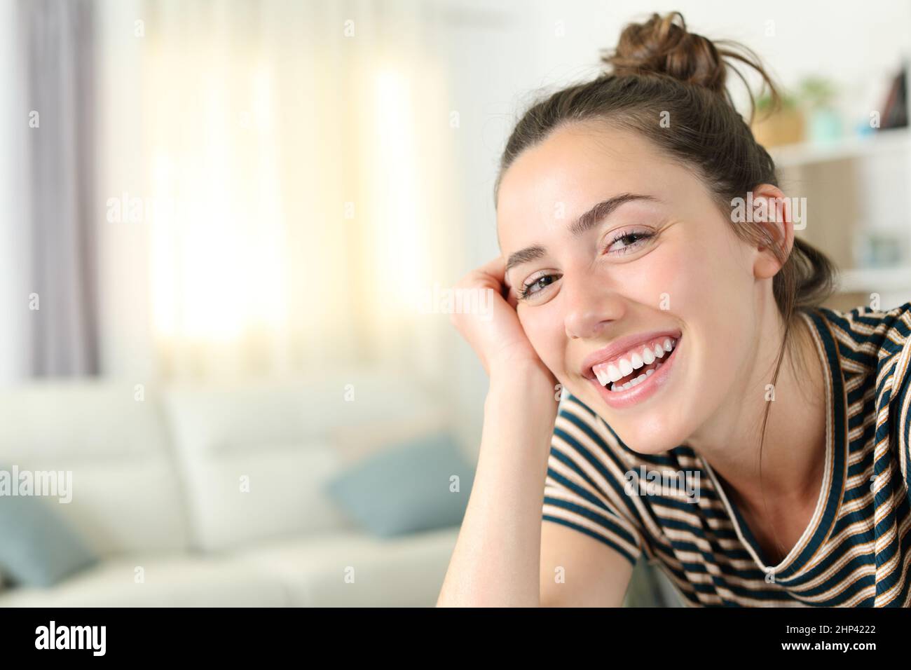 Happy woman with perfect smile at home looks at you with copy space ...