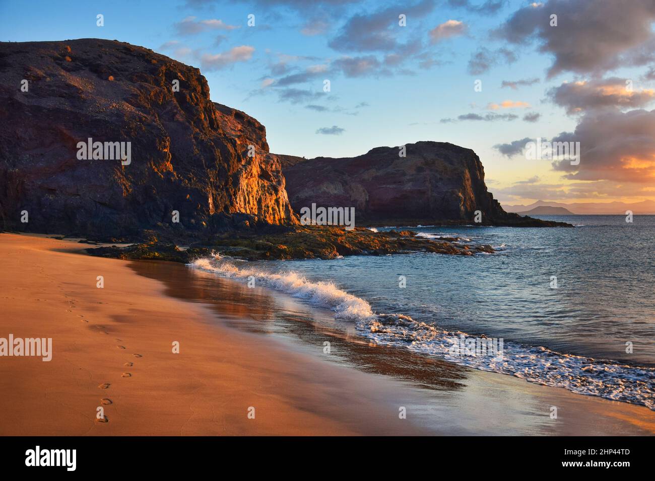 The west coast of Lanzarote at sunset. A sandy beach and a blue sky ...