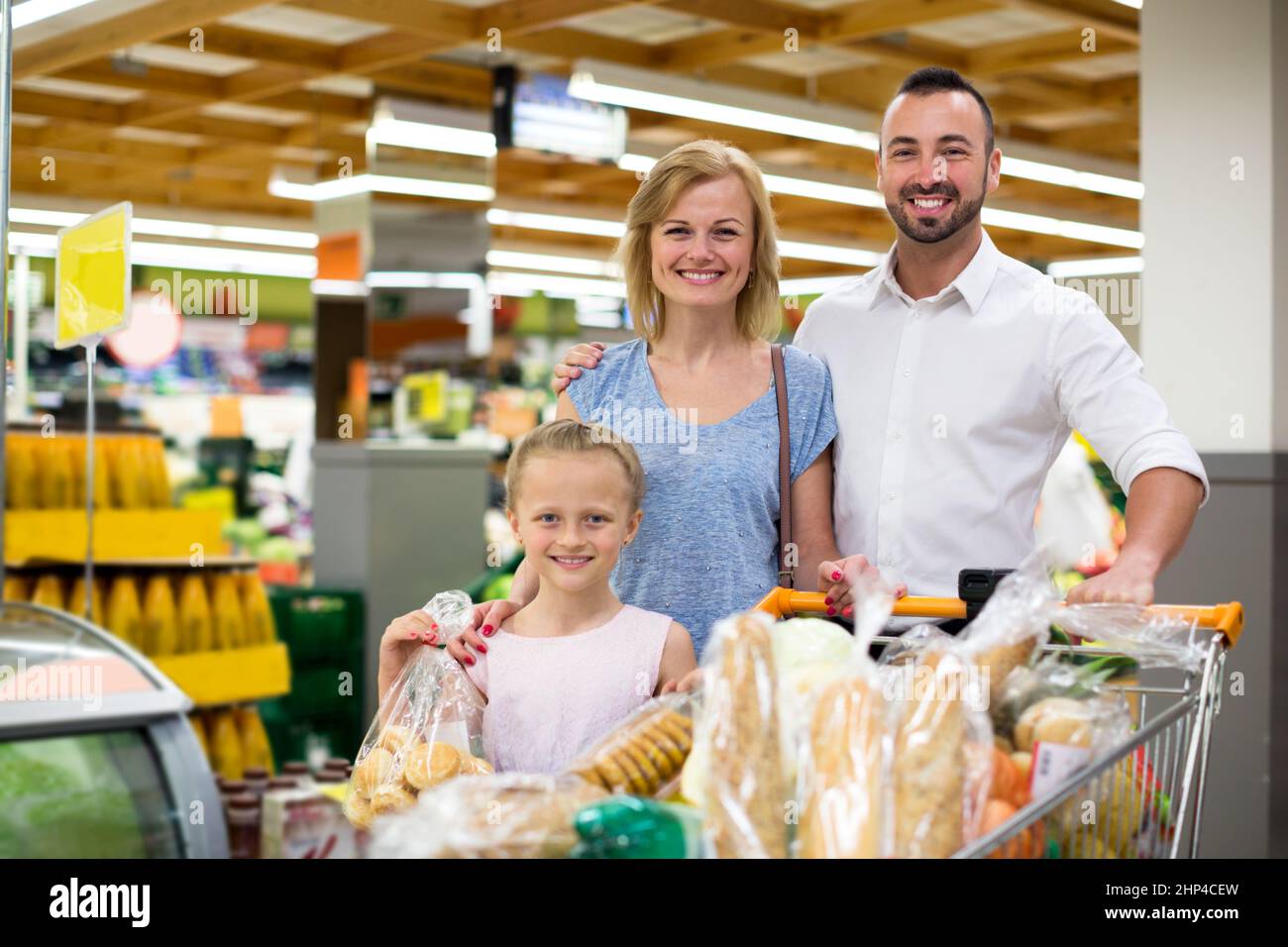 Happy family standing with full cart in supermarket Stock Photo - Alamy