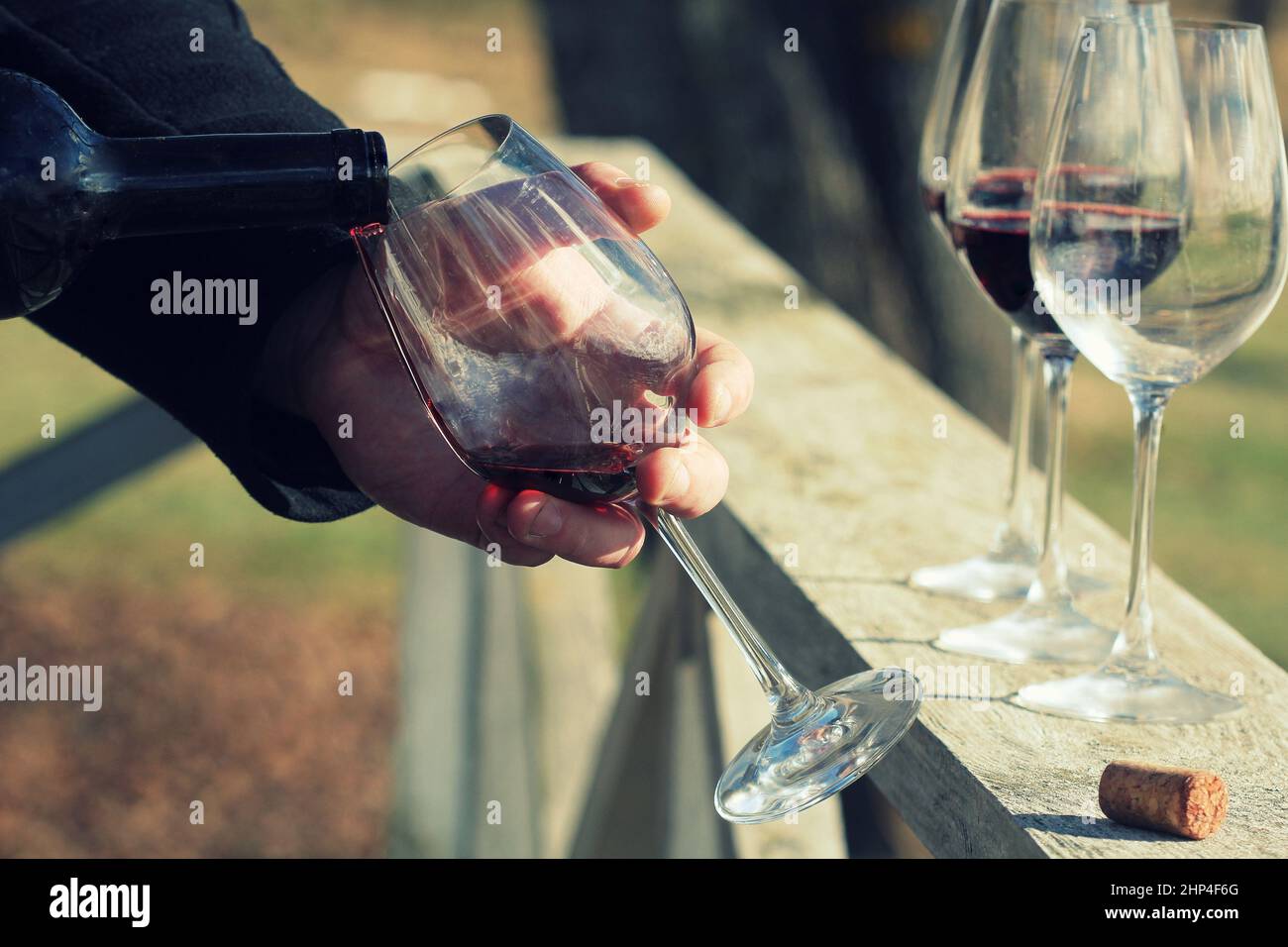 Man hand pouring red wine from the bottle into glasses with friends ...