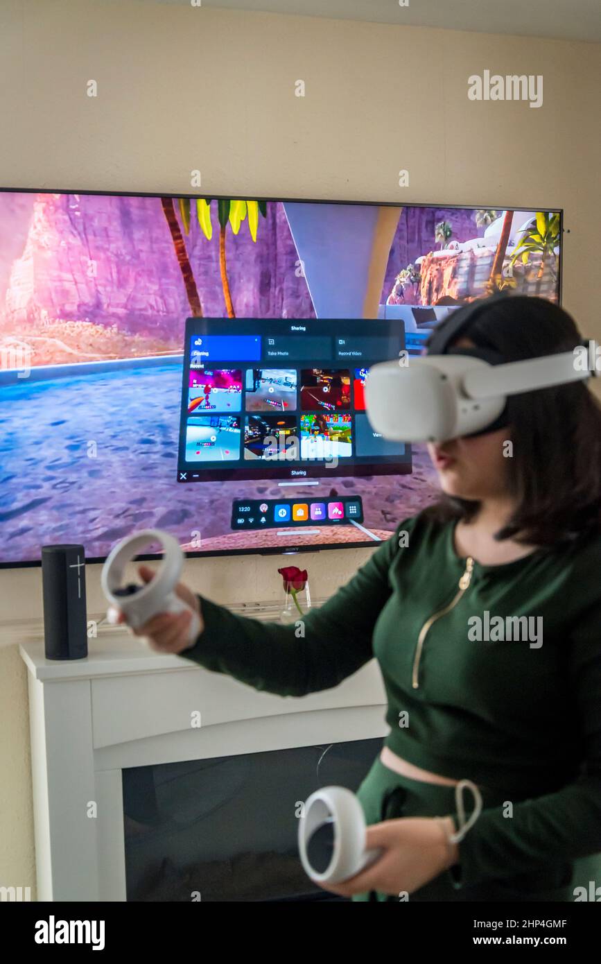 Girl with VR headset and two controllers playing with friends in ...