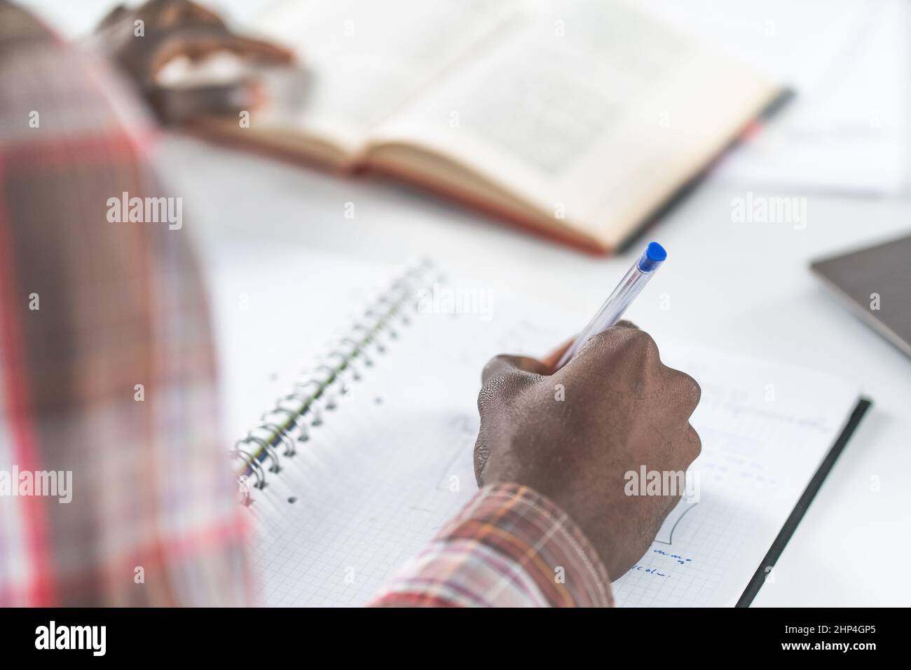 Close up on young african american male hand making notes reading a ...