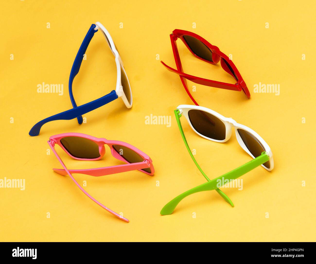 Modern plastic sunglasses with colorful frames on yellow background ...