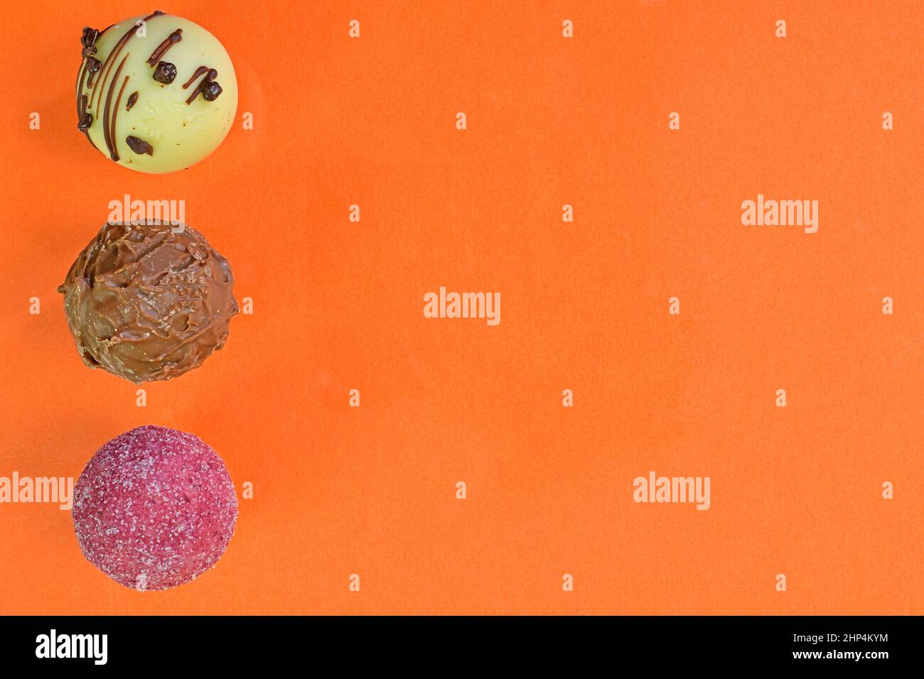 Chocolate bonbons or pralines on an orange pastel background ...