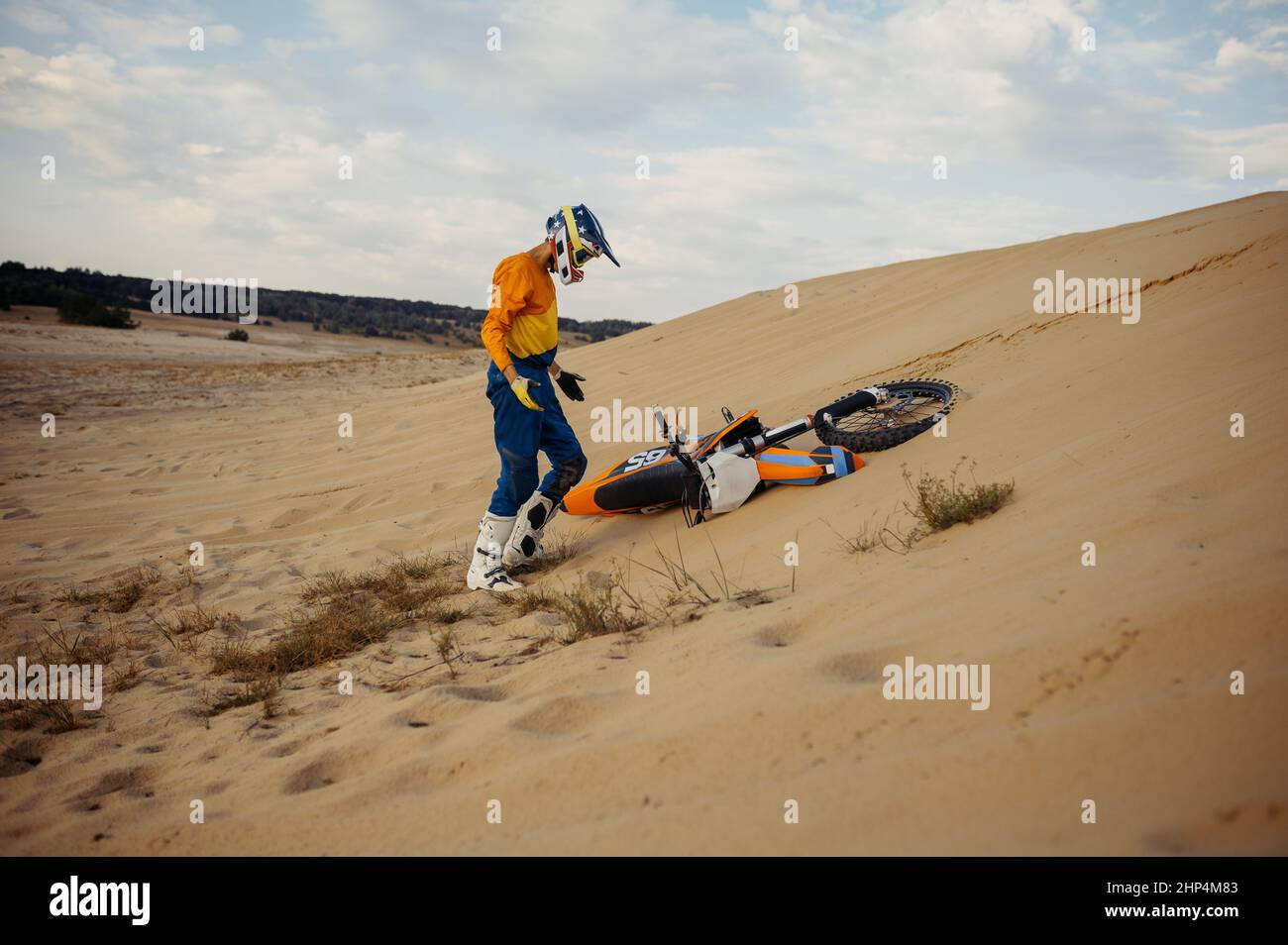 Motocross rider in helmet picking up motorcycle scooter after falling ...
