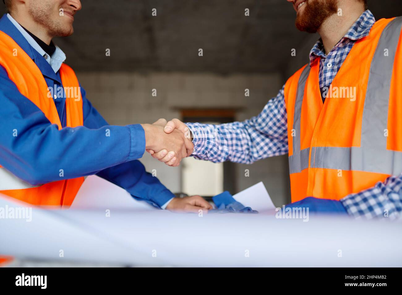 Builder and engineer handshake over paper blueprint after finish ...