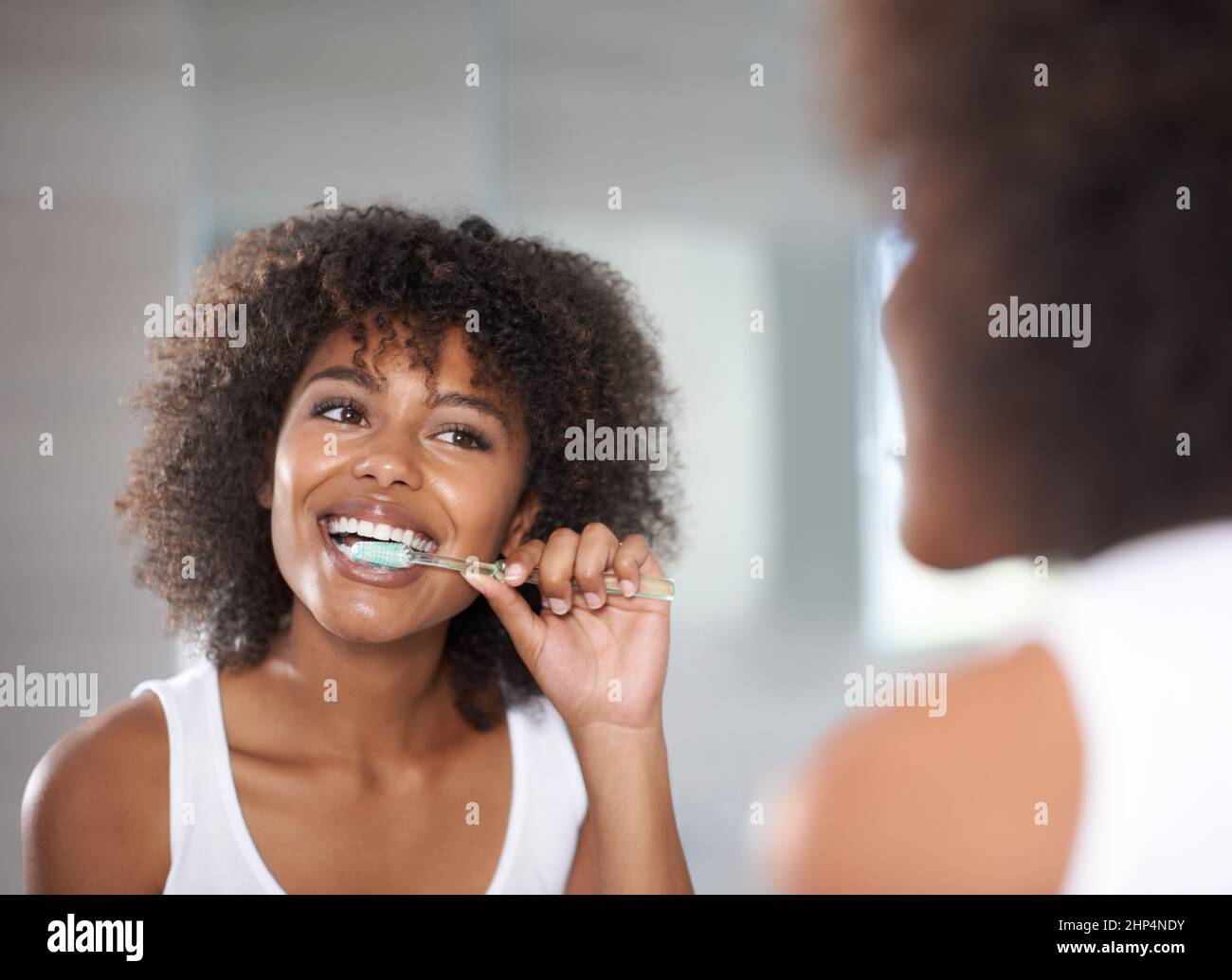Keeping her smile. Shot of a a young woman brushing her teeth Stock ...