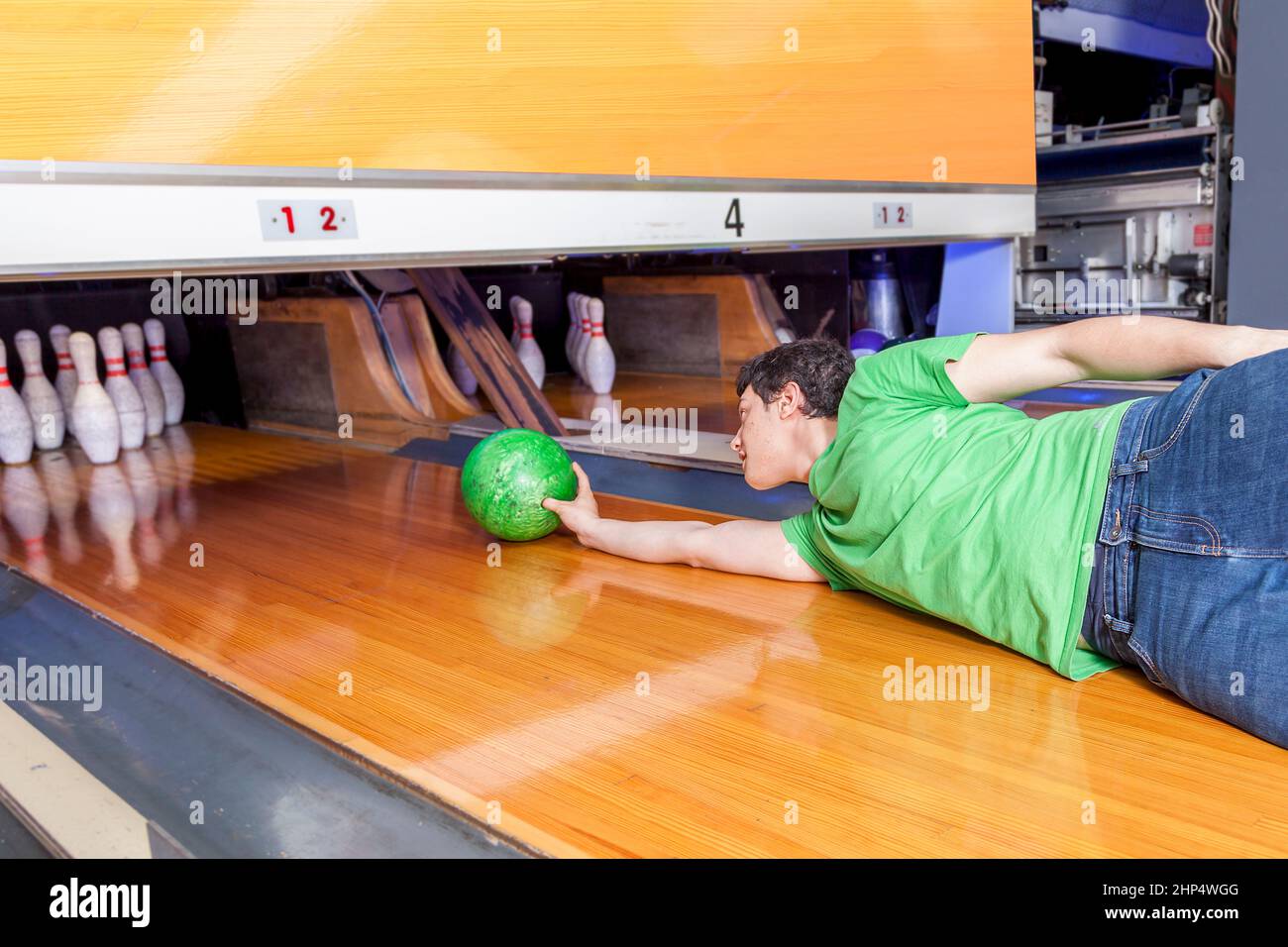 young man sliding down a bowling alley Stock Photo - Alamy