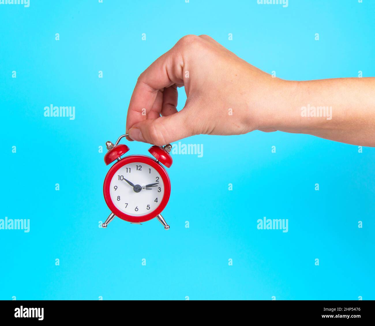 Alarm clock red color in woman hand on bright blue background Stock ...