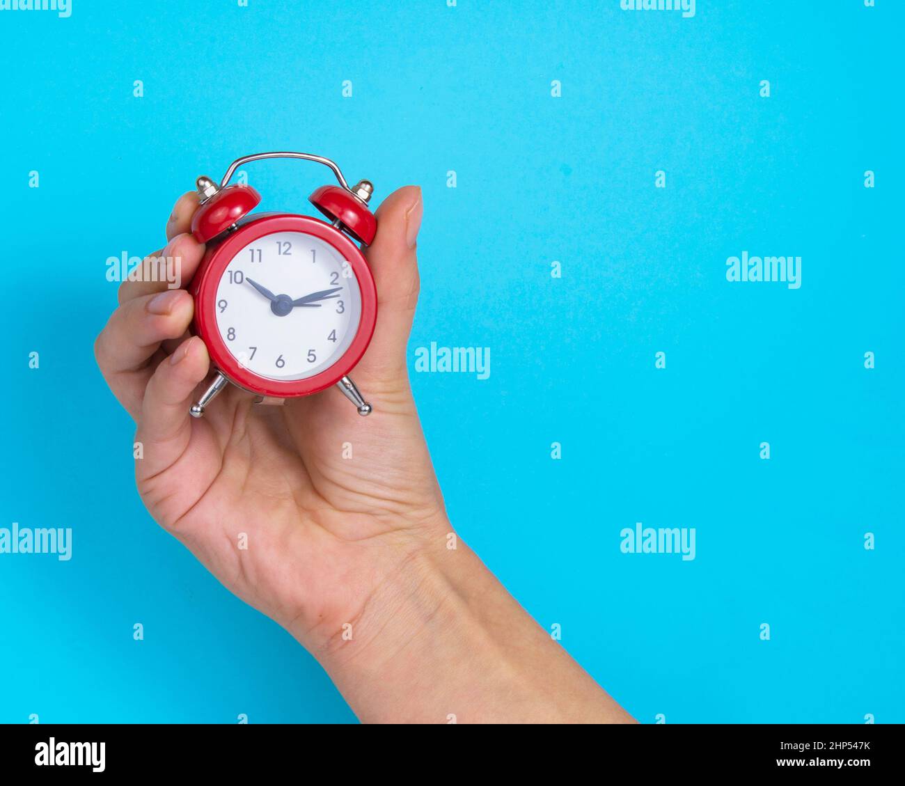 Alarm clock red color in woman hand on bright blue background Stock ...