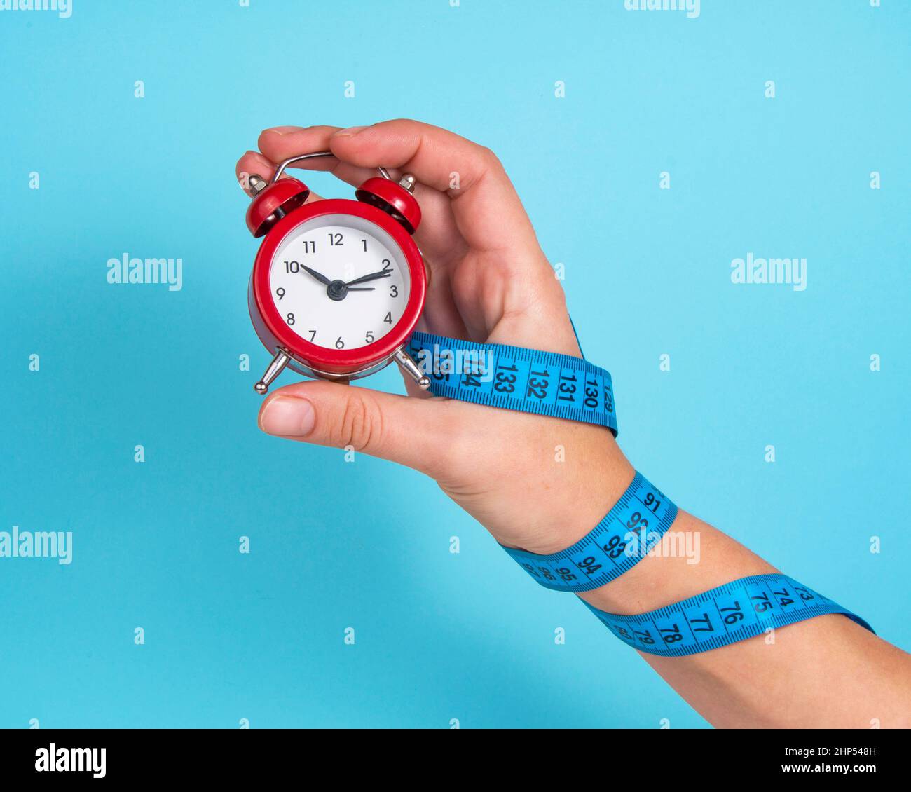 Alarm clock red color in woman hand on bright blue background Stock ...