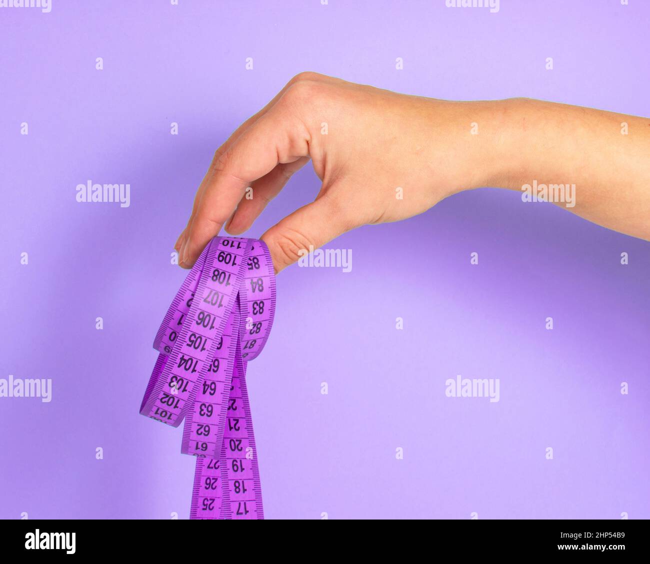 Purple tape measure diet concept on woman hand on violet bright ...