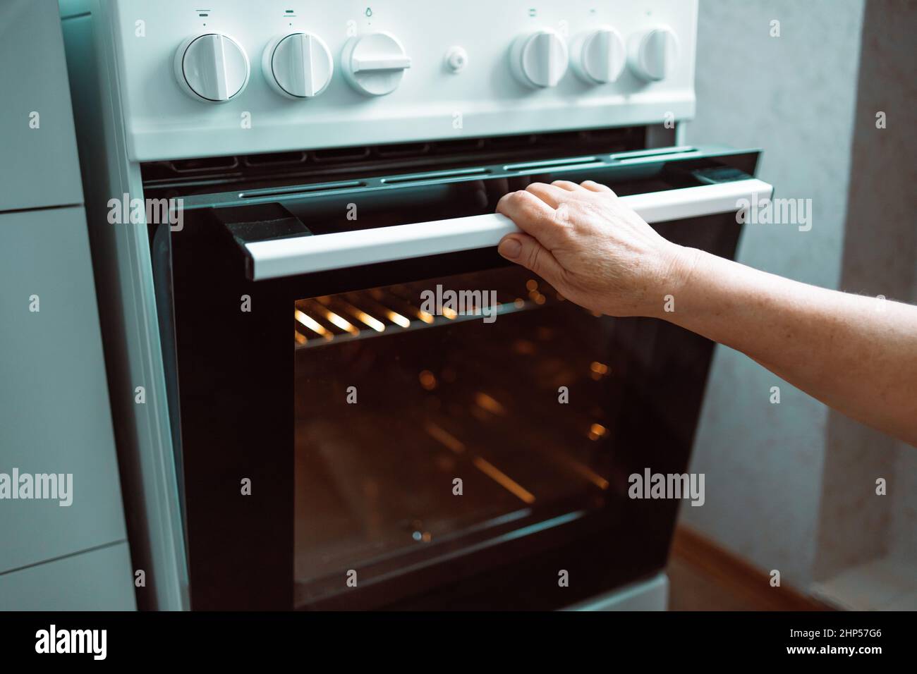 Woman hand opening oven door and light is on in kitchen at home Stock ...