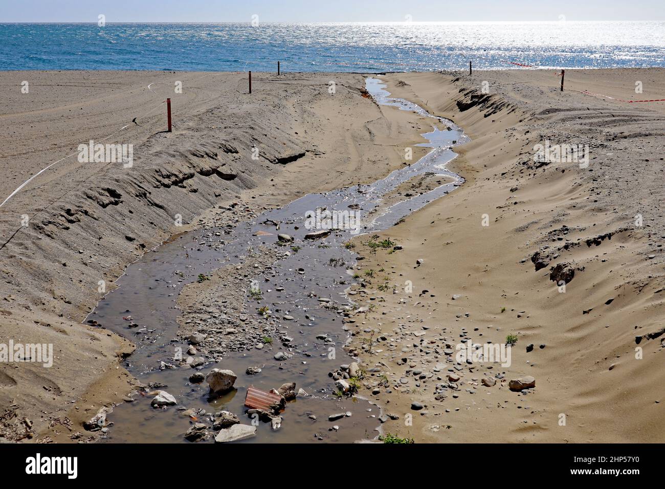 A stream flows across the beach in Estepona in Spain. It is taped off ...
