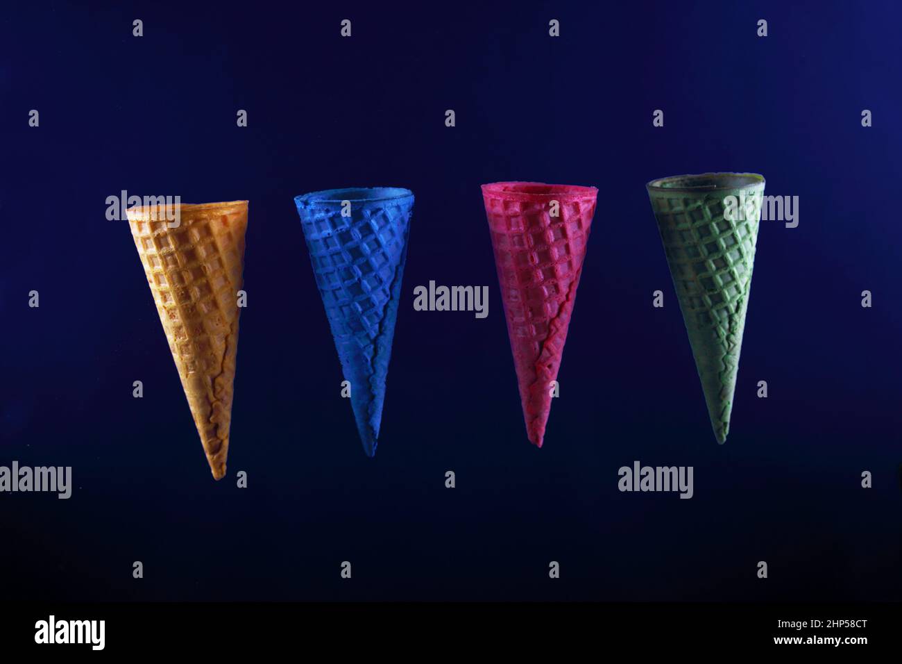 four waffle cones of different colours isolated against blue background ...