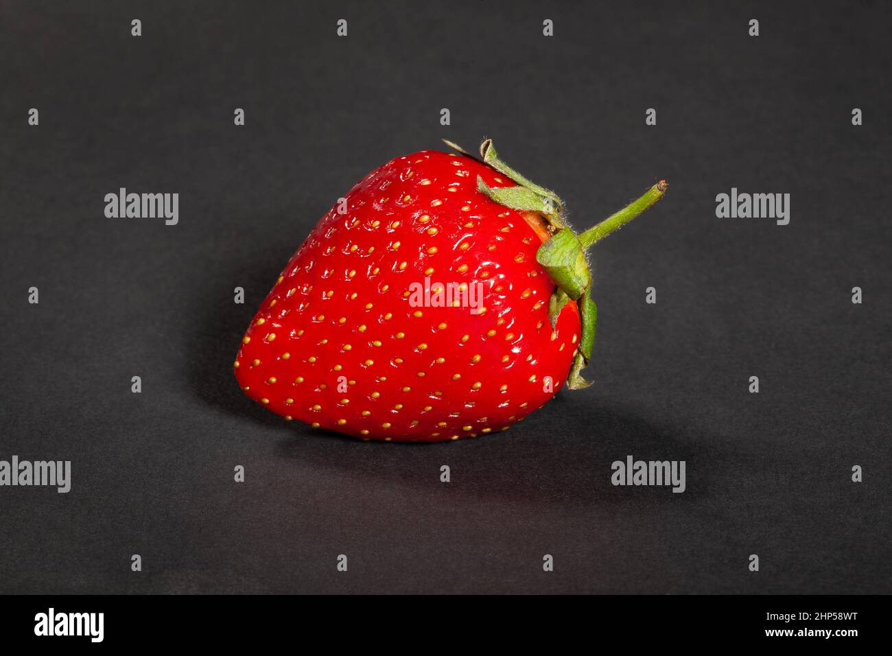 single strawberry on black background Stock Photo - Alamy
